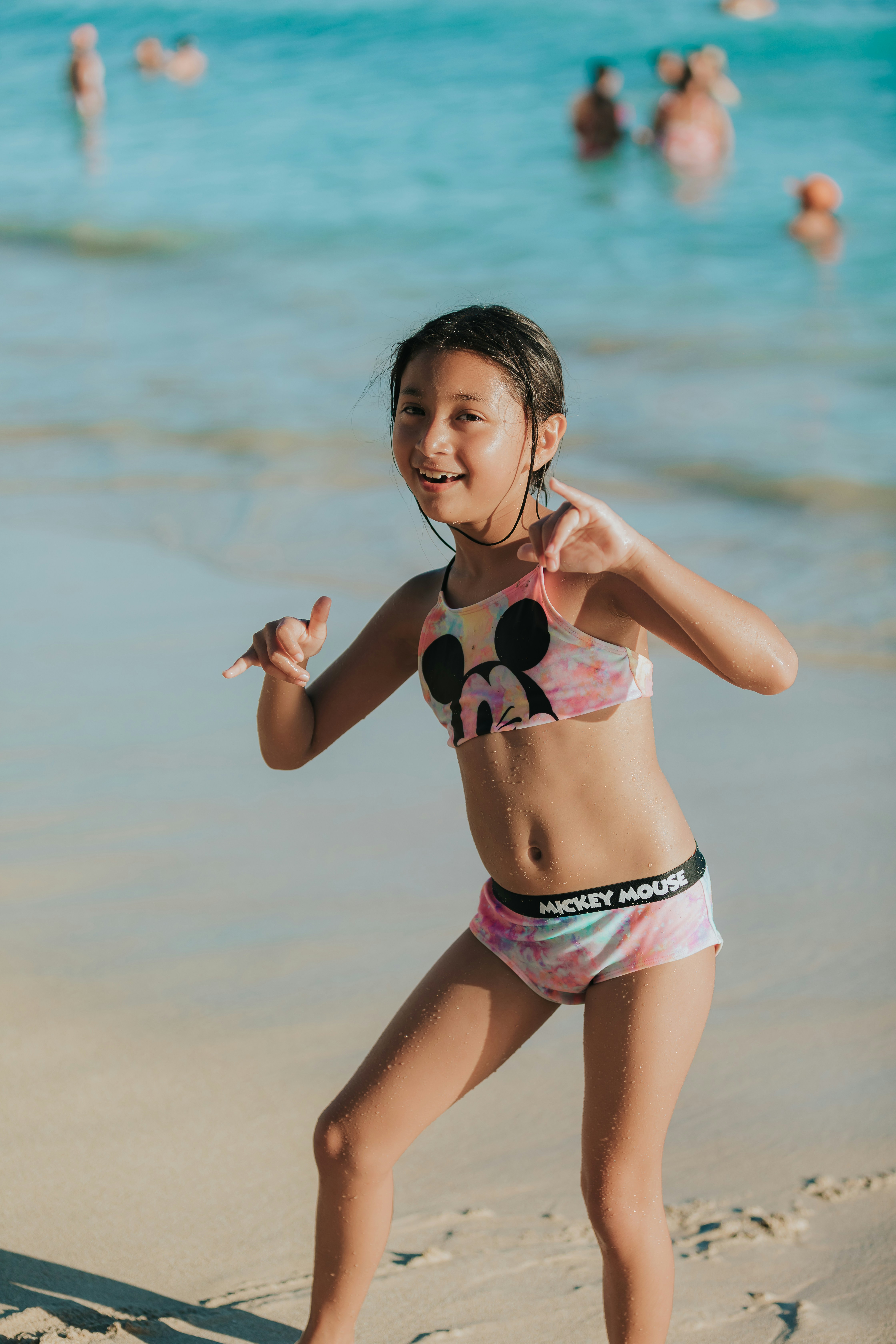 Sunlit Sprint: A Girl in a Mickey-Mouse Bikini Dances at the Shore