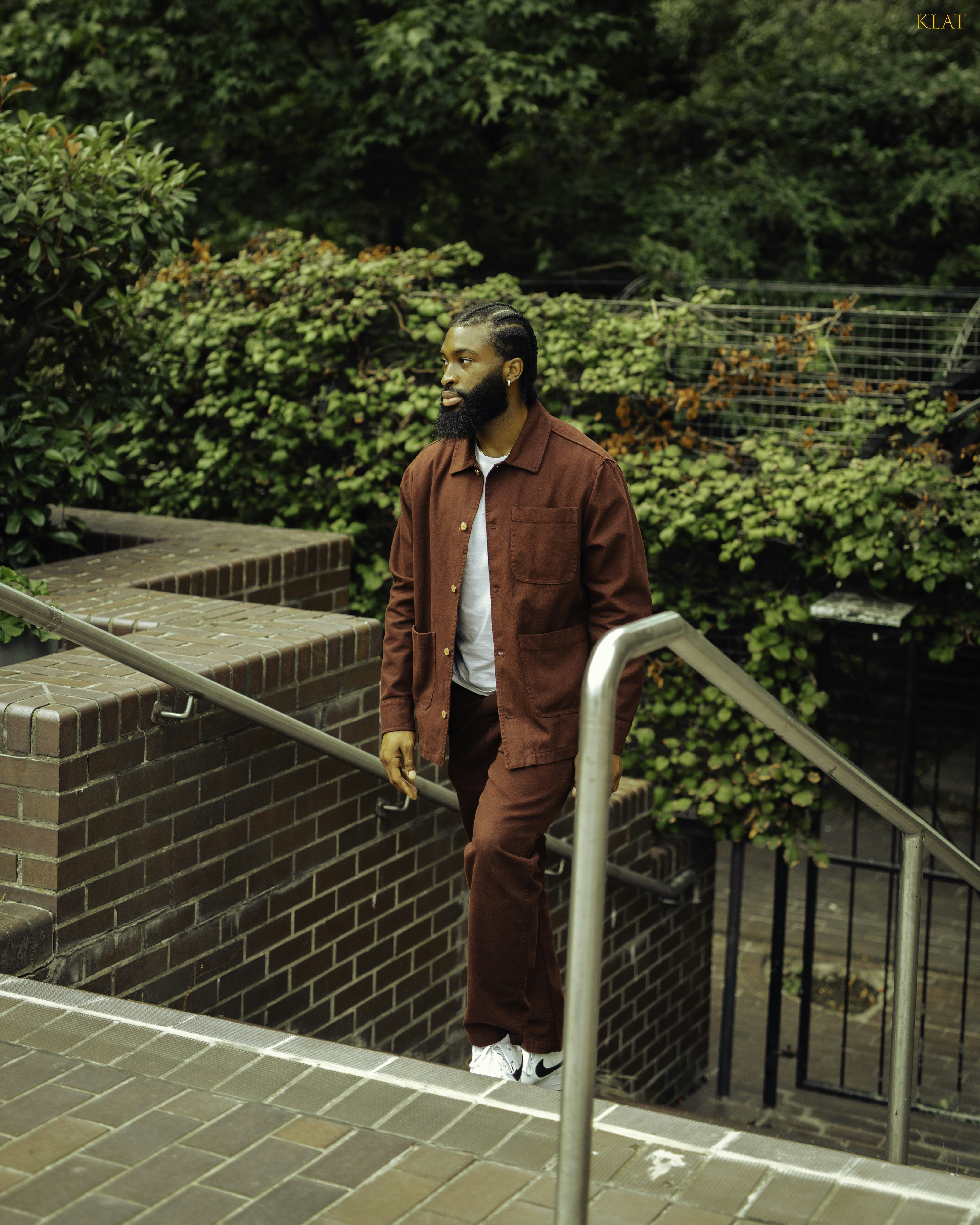 Man in Rust-Red Jumpsuit Descends a Brick Staircase