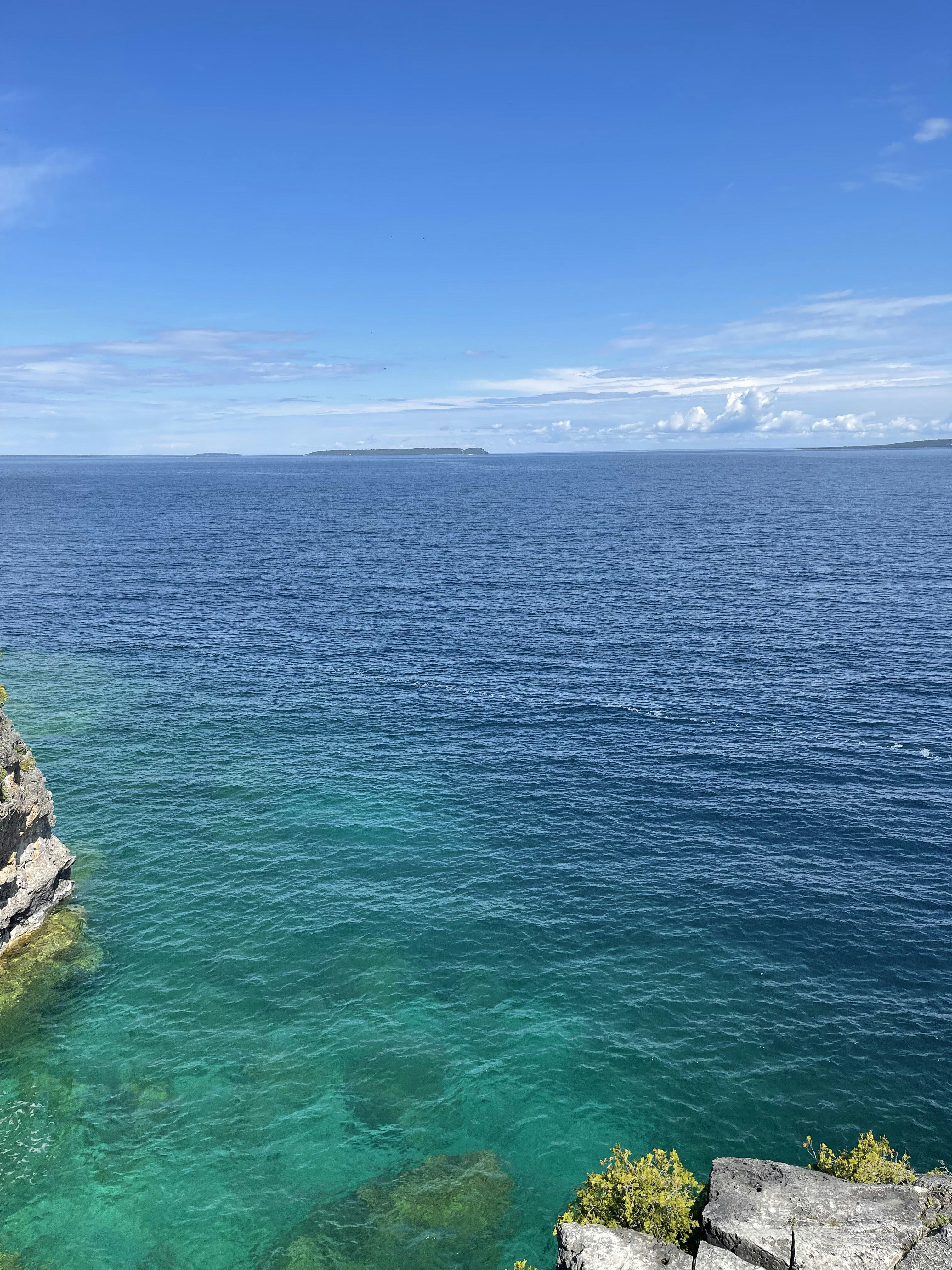 Vibrant turquoise waters meet rocky shore under a clear blue sky, highlighting the tranquility of nature.