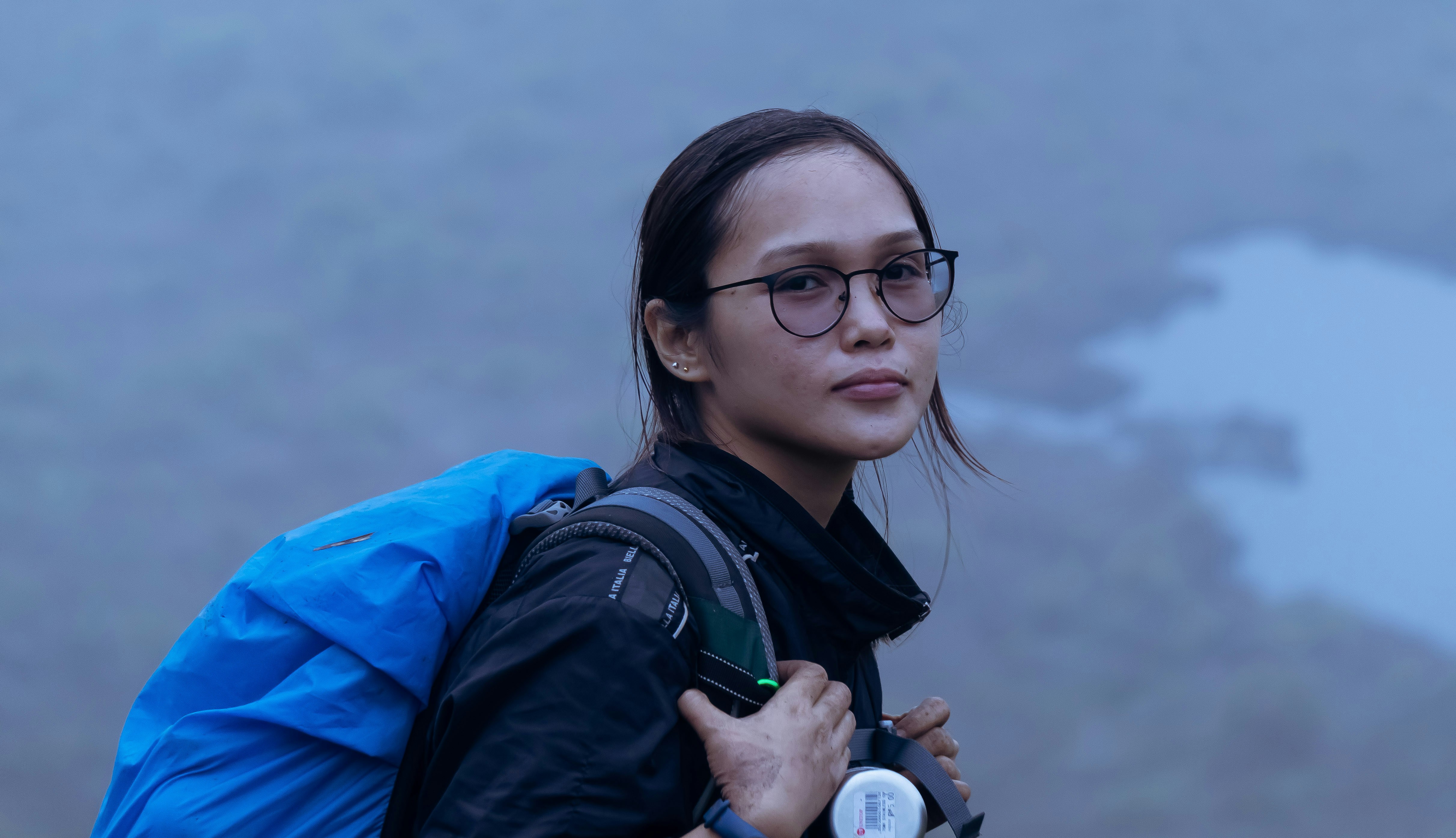 Ridgebound Pause: A Hiker with a Blue Pack in Mist