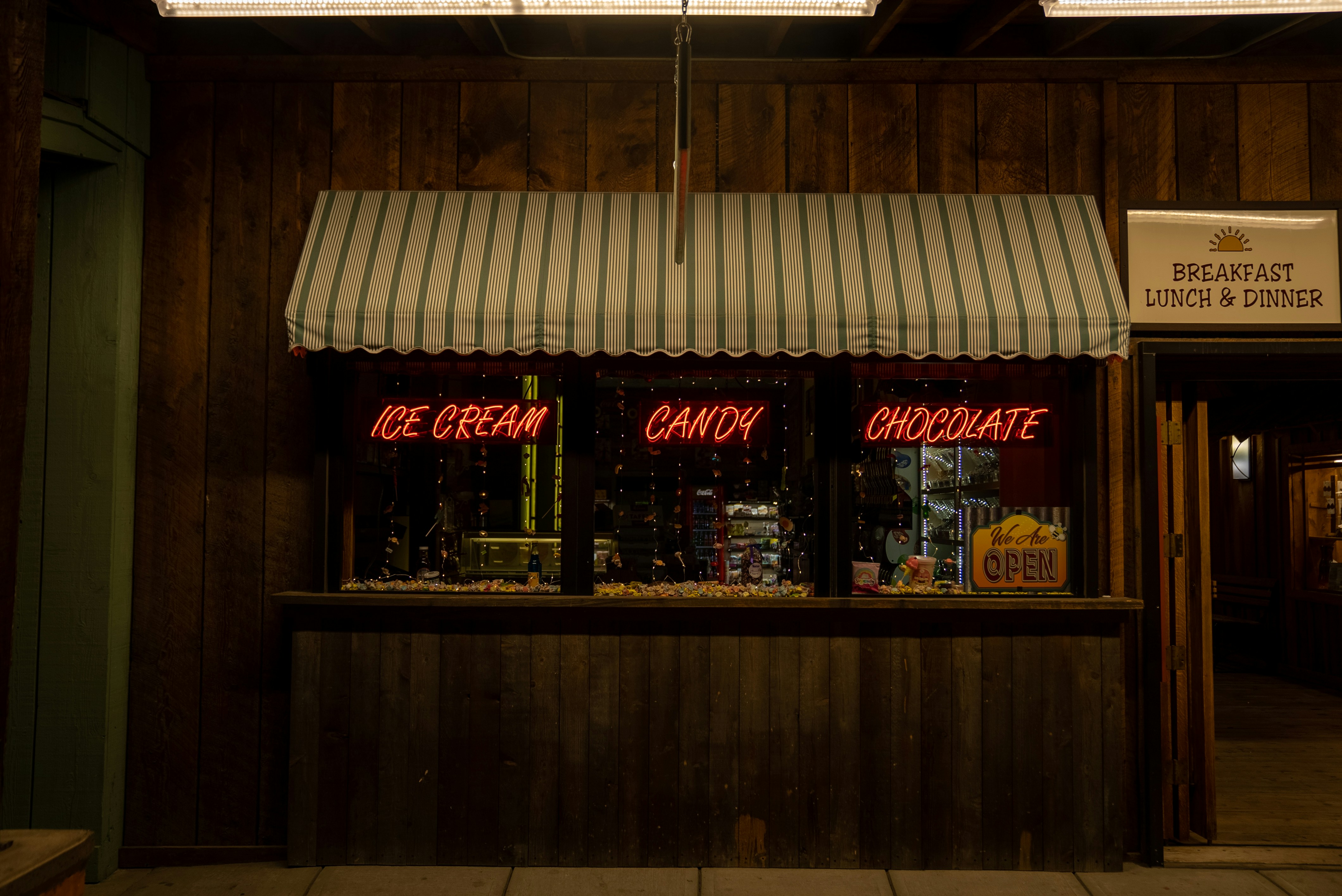 Neon Window of Sweet Delights under a Striped Awning