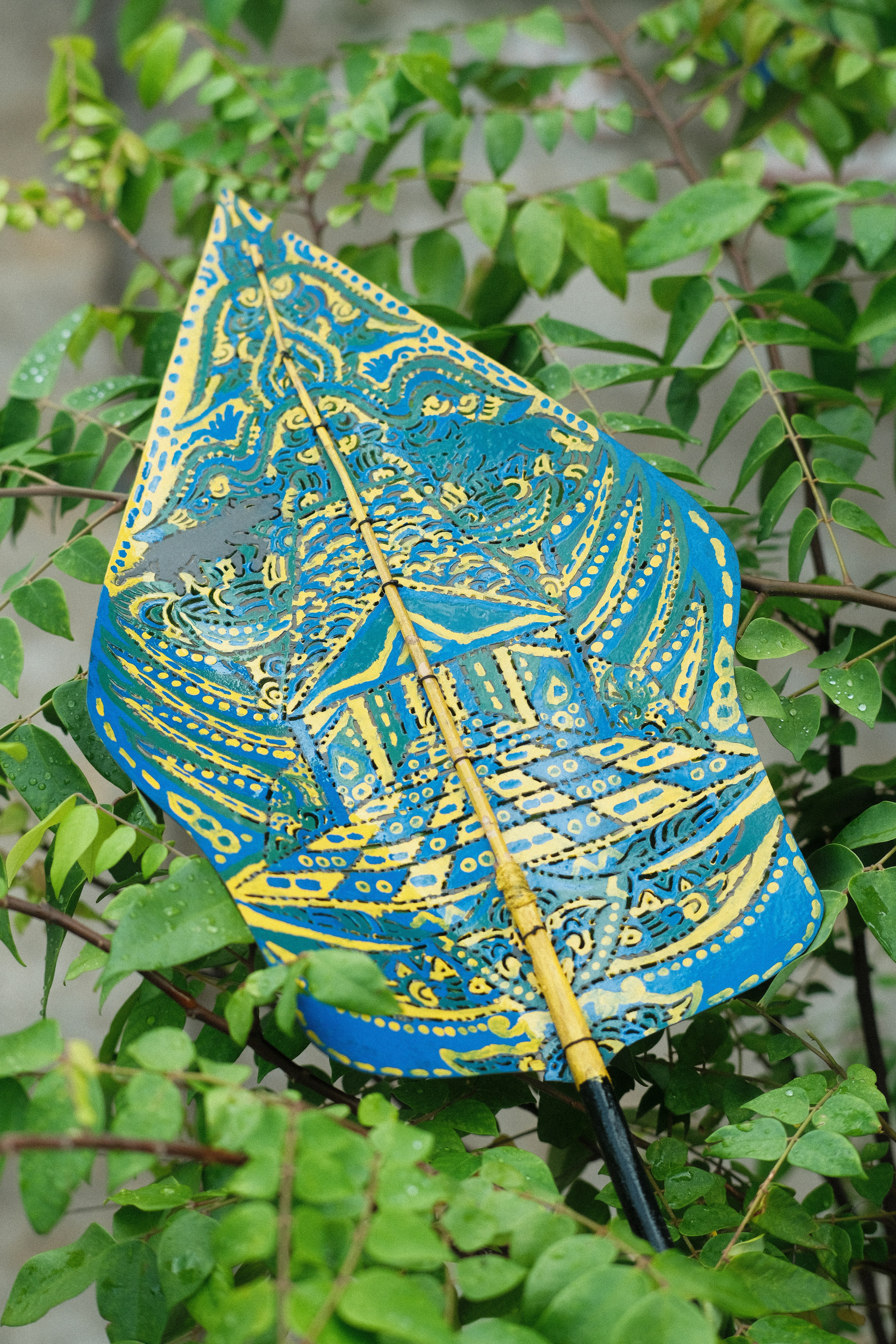 Blue-Gold Lacework Umbrella Resting Among Verdant Foliage