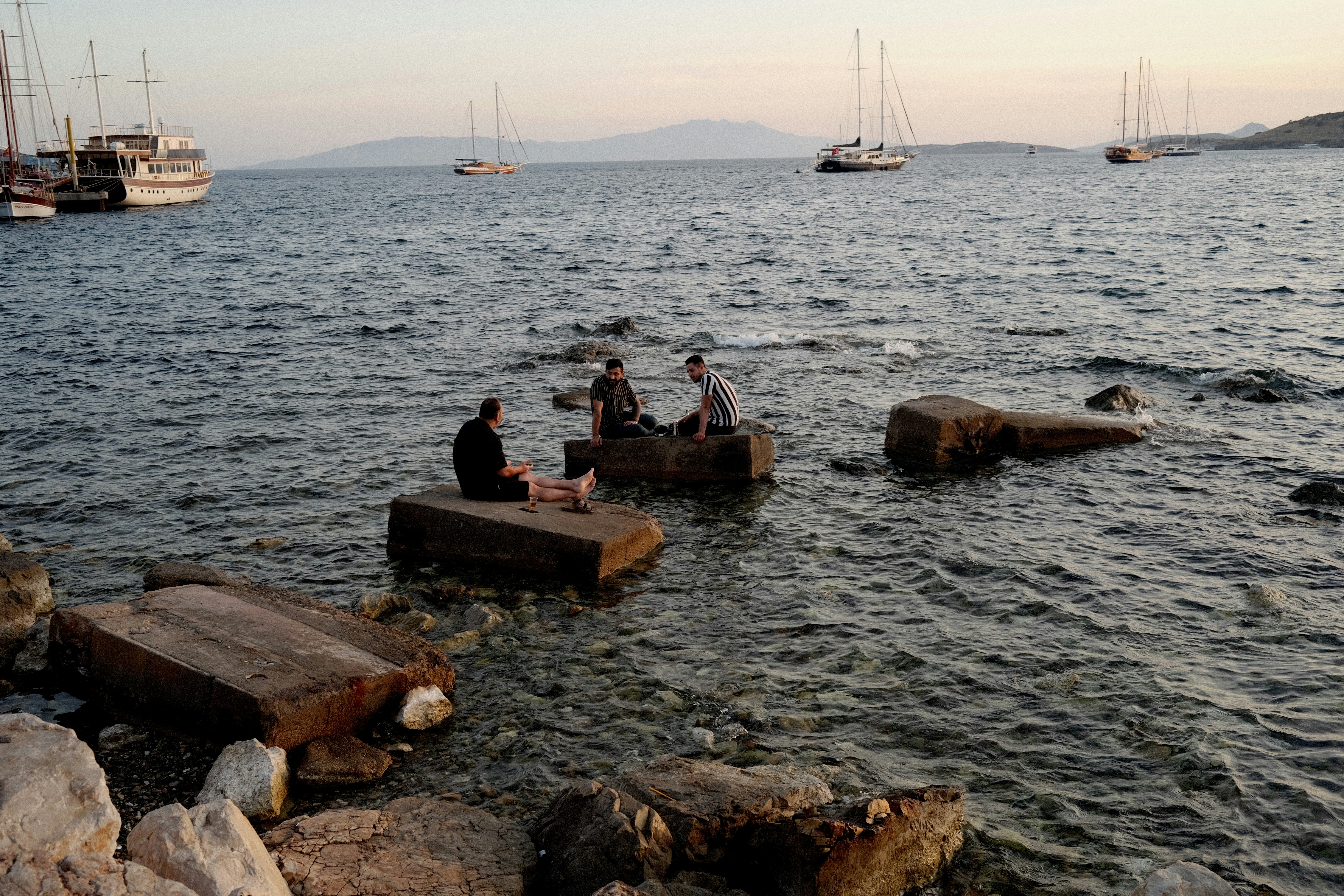 A group of people sitting on a dock in the water photo – Free Person ...