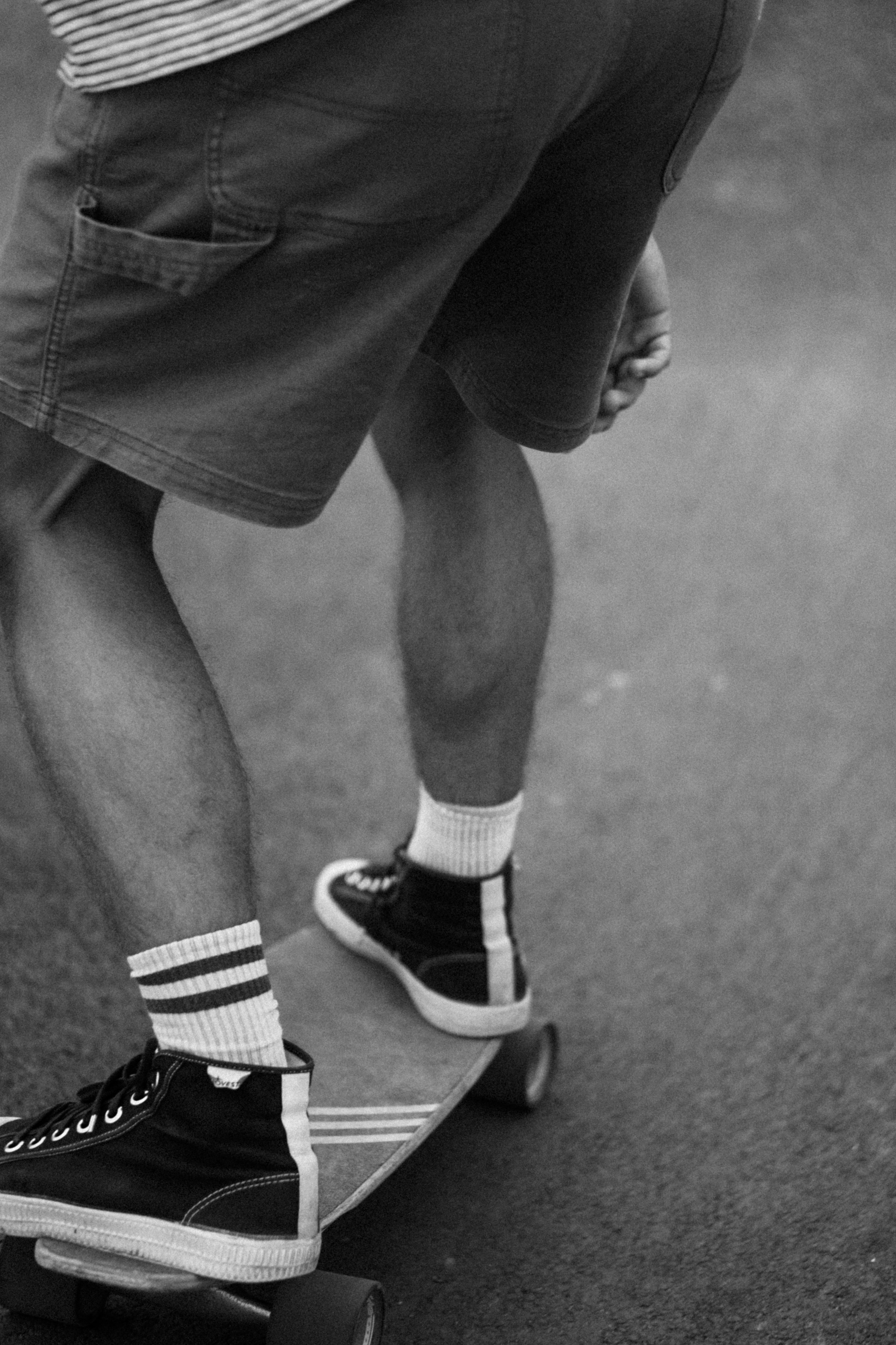 A skateboarder in motion, showcasing dynamic leg positioning and stylish footwear on a smooth urban surface.