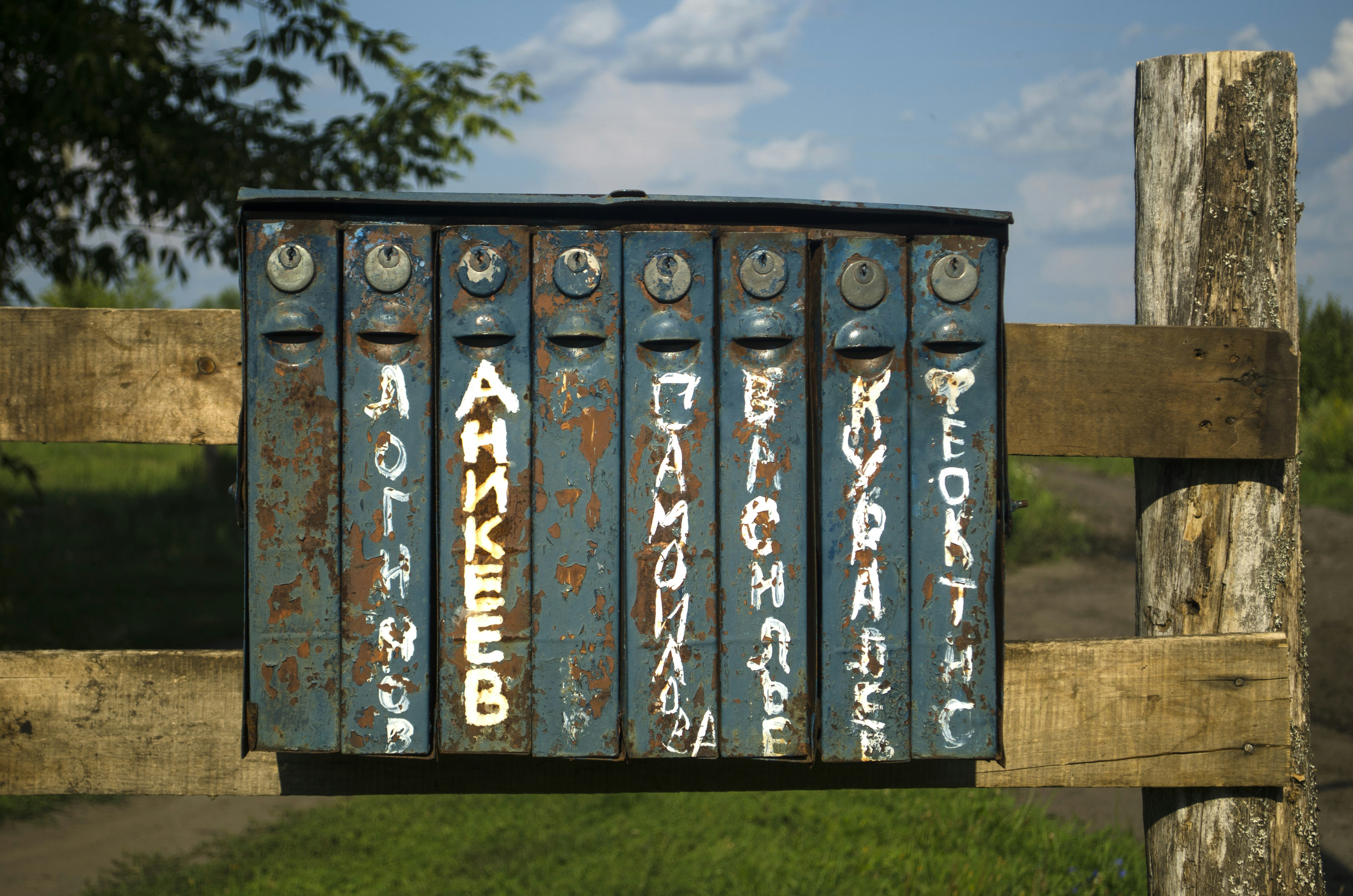 Rusty Mailbox Row on a Sunlit Fence