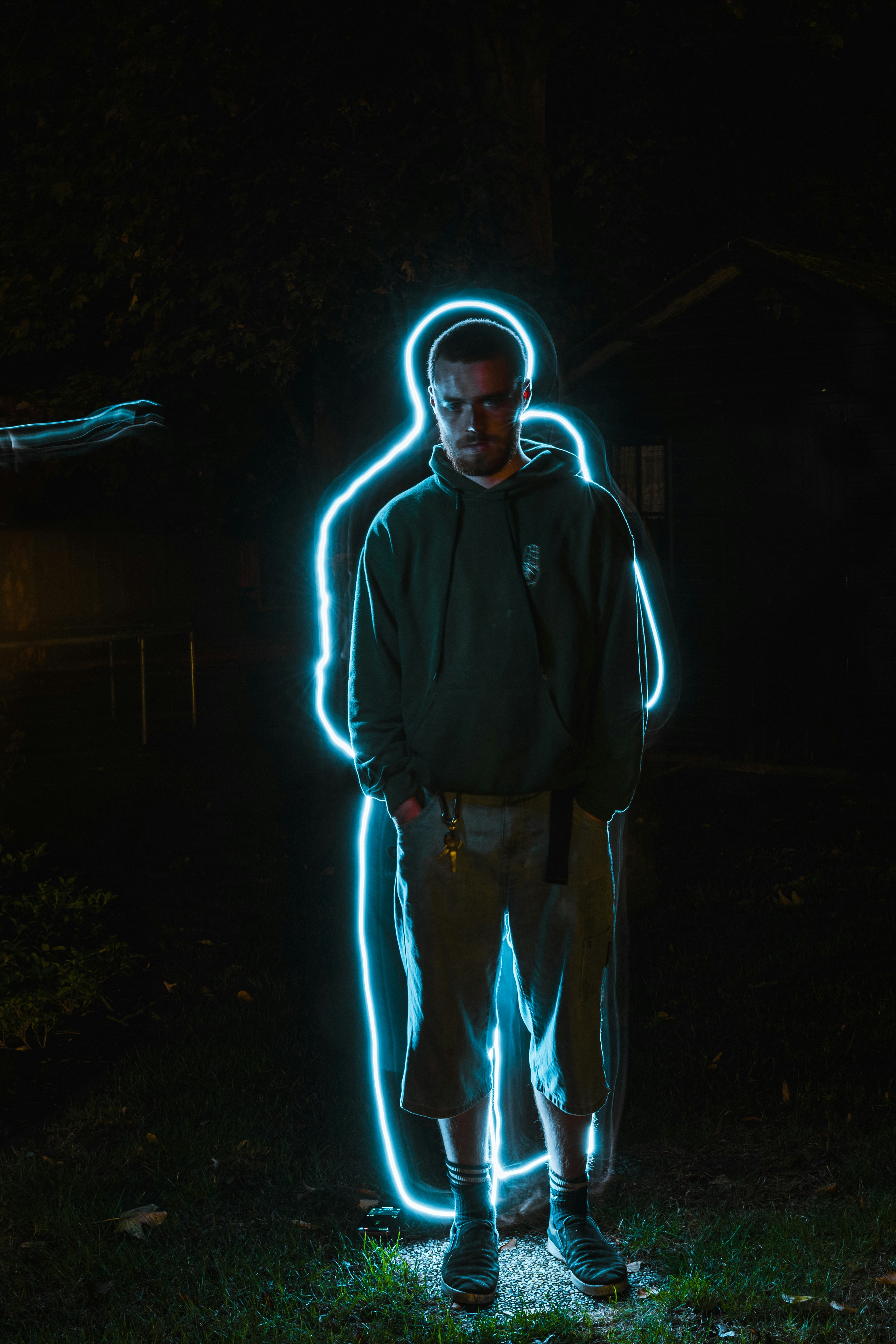 A figure stands illuminated by a glowing outline, set against a dark background, suggesting a connection between the physical and the ethereal.