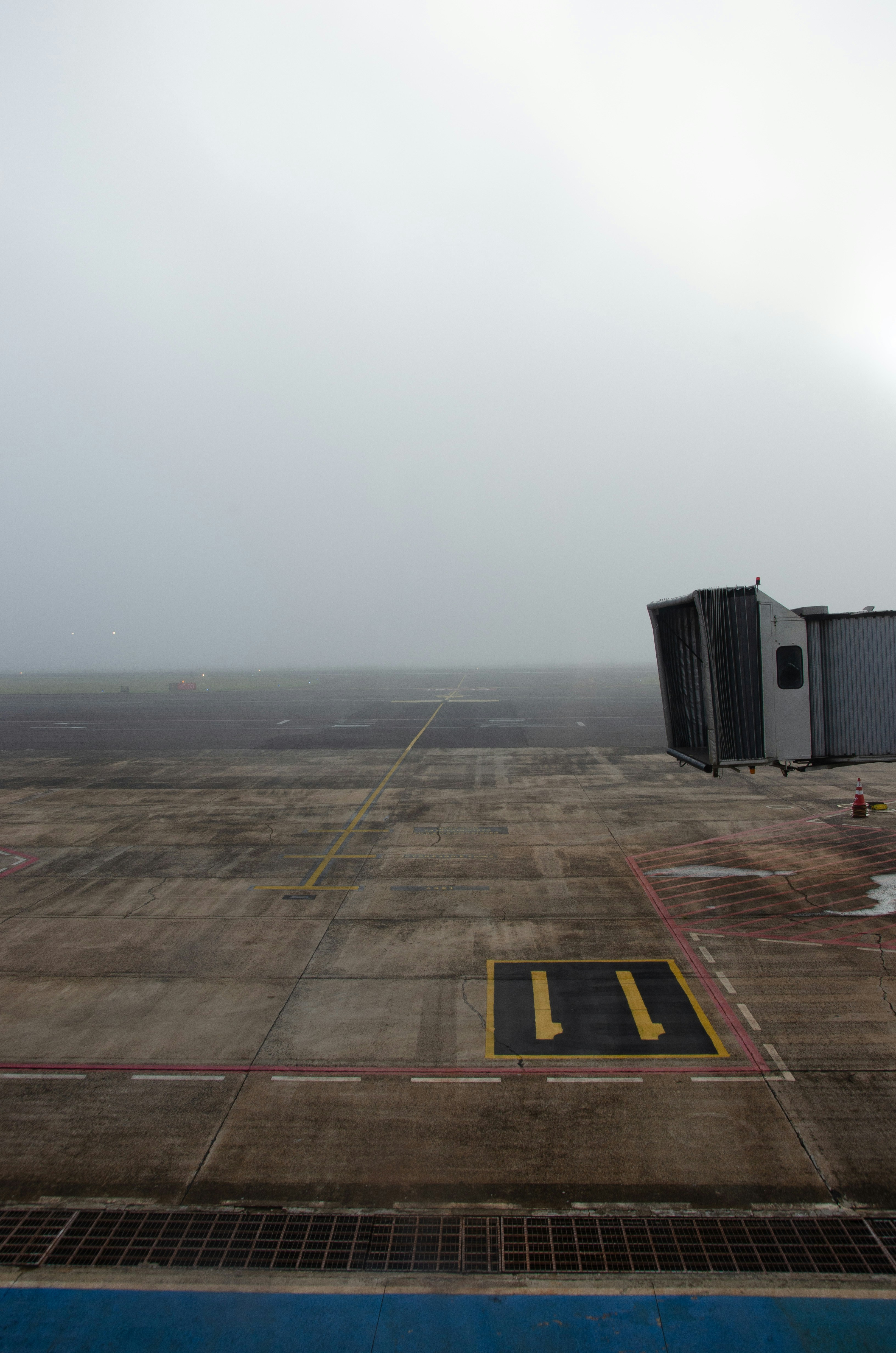 Idle Jet Bridge on a Fogbound Apron under a Pale Horizon