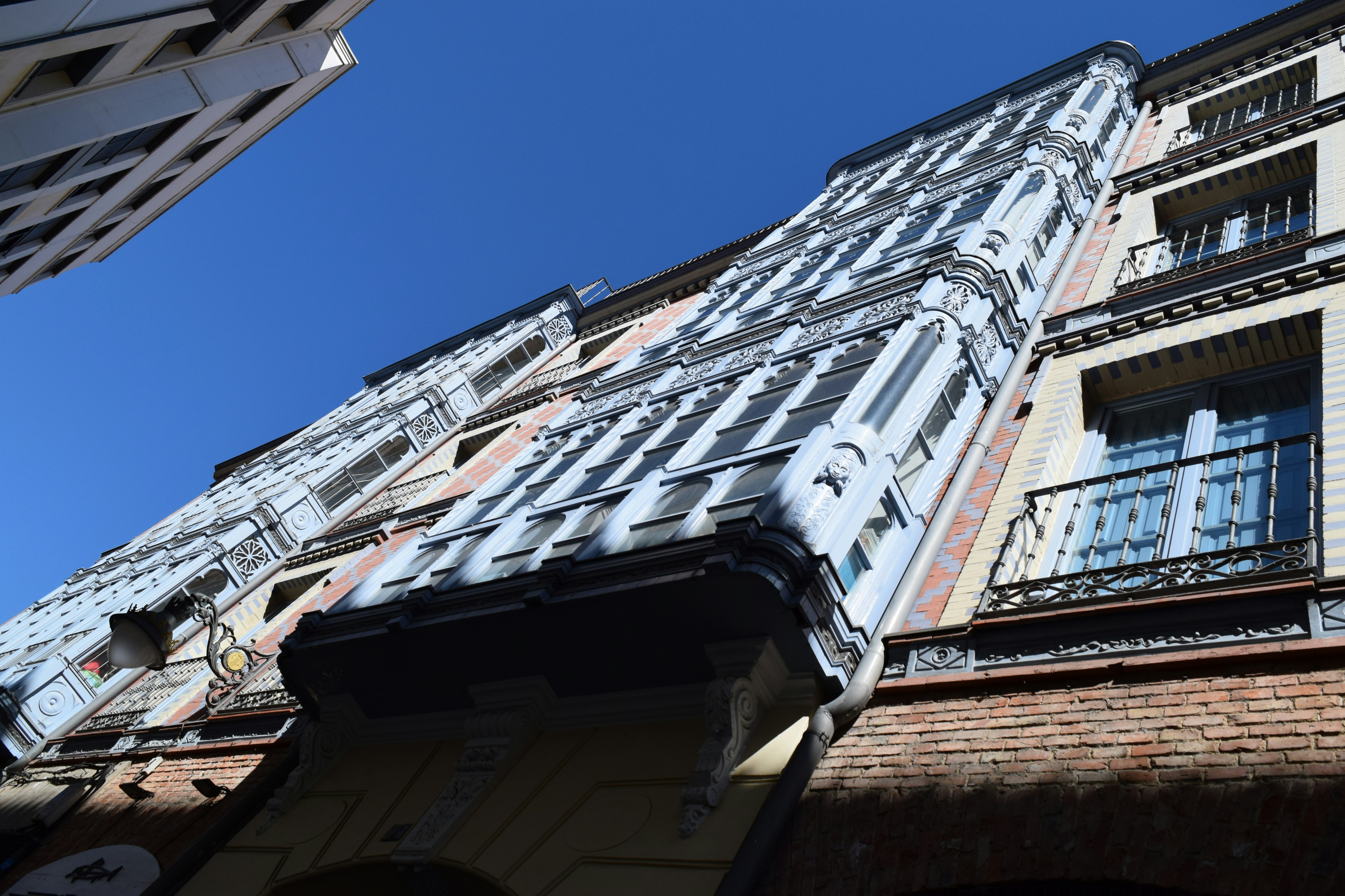 Ornate building facade with intricate balconies against a vivid blue sky.