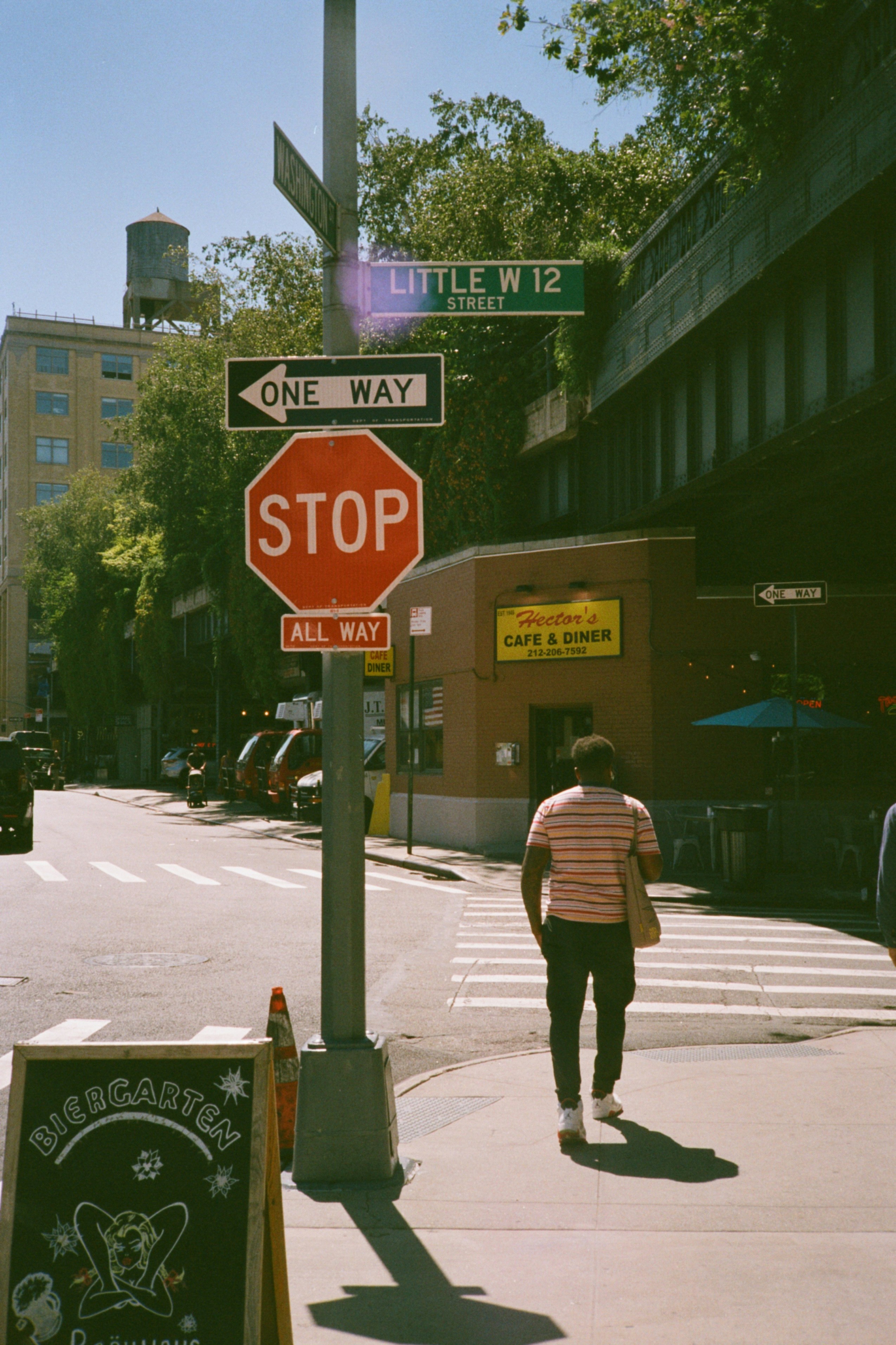 A person walking down a sidewalk next to a stop sign photo – Free Ny ...