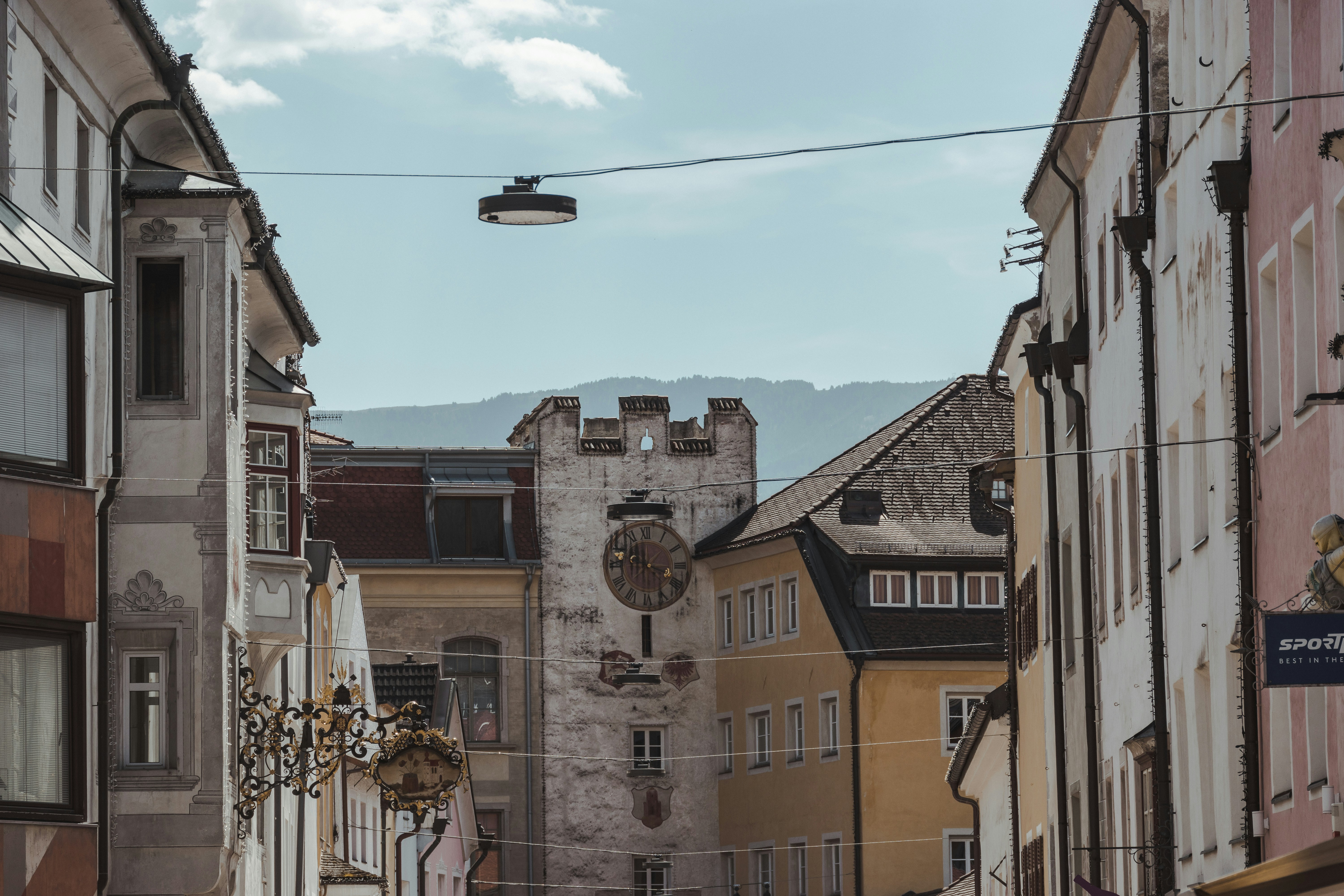 Clocktower Gate: Sunlit European Street Framed by Pastel Facades