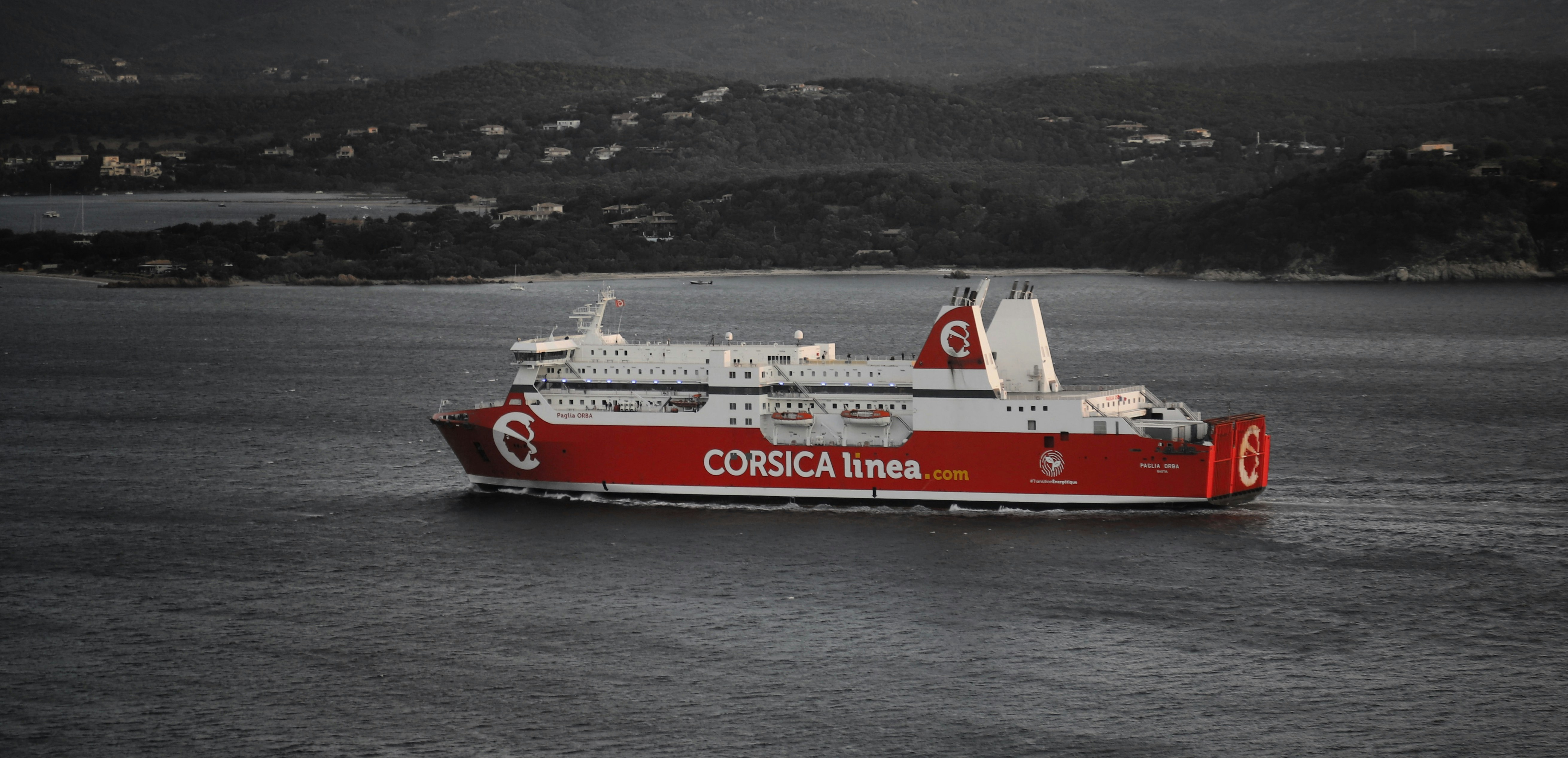 Corsican Roamer: Red Ferry Slicing Through Quiet Waters