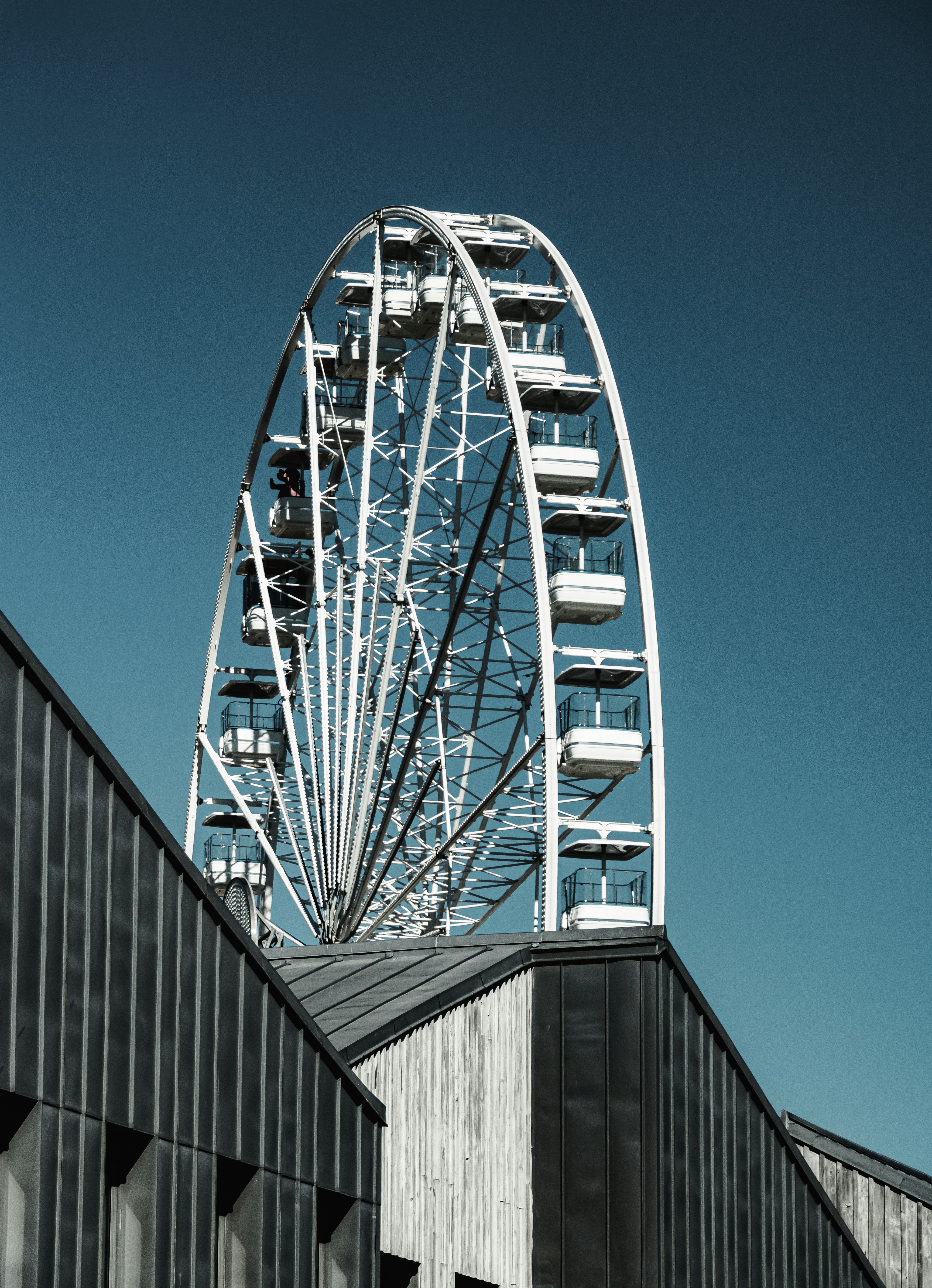 Geometric Rooftops Frame a Skyward Ferris Wheel