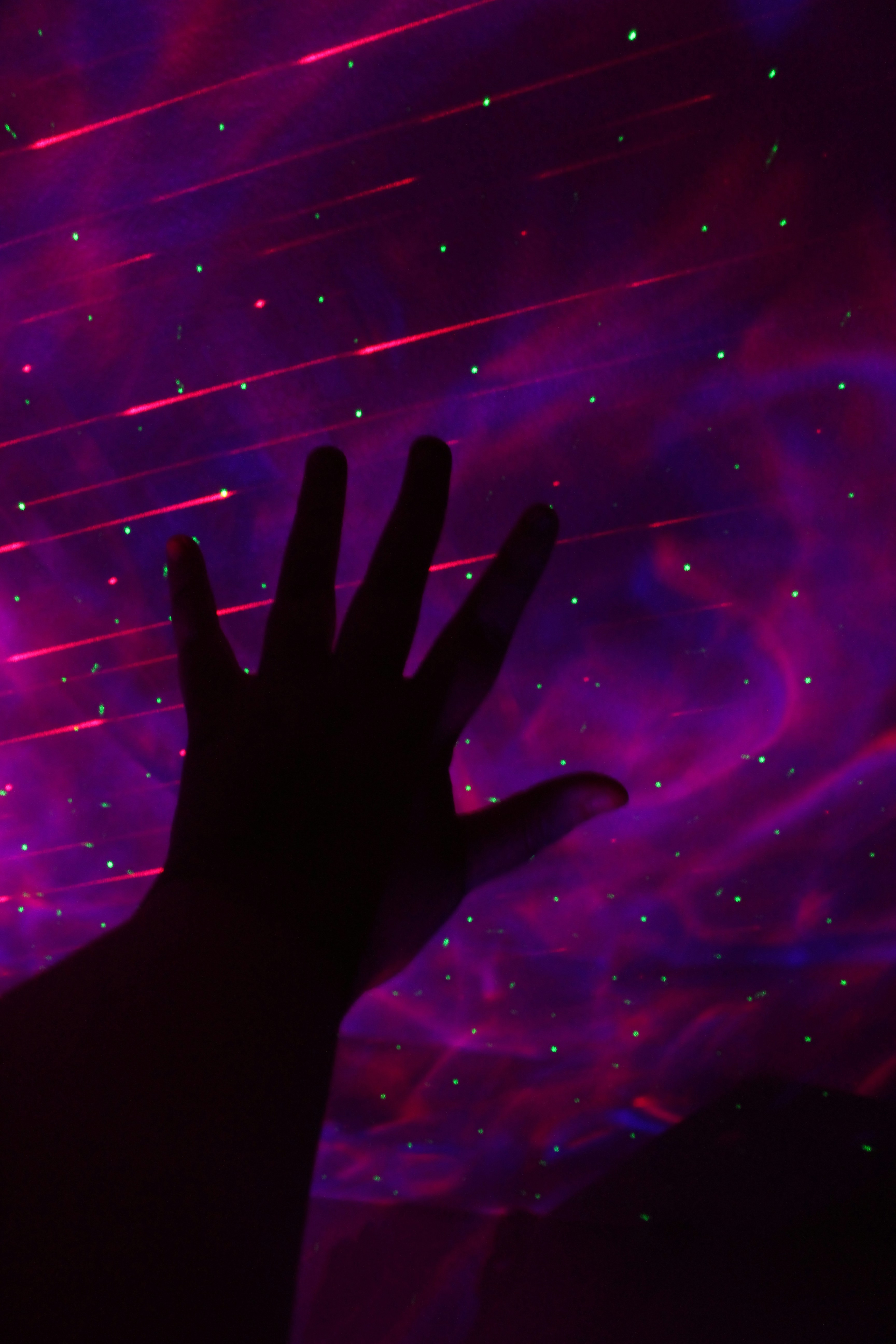 Silhouetted Hand Reaching Into a Neon Nebula of Laser Light