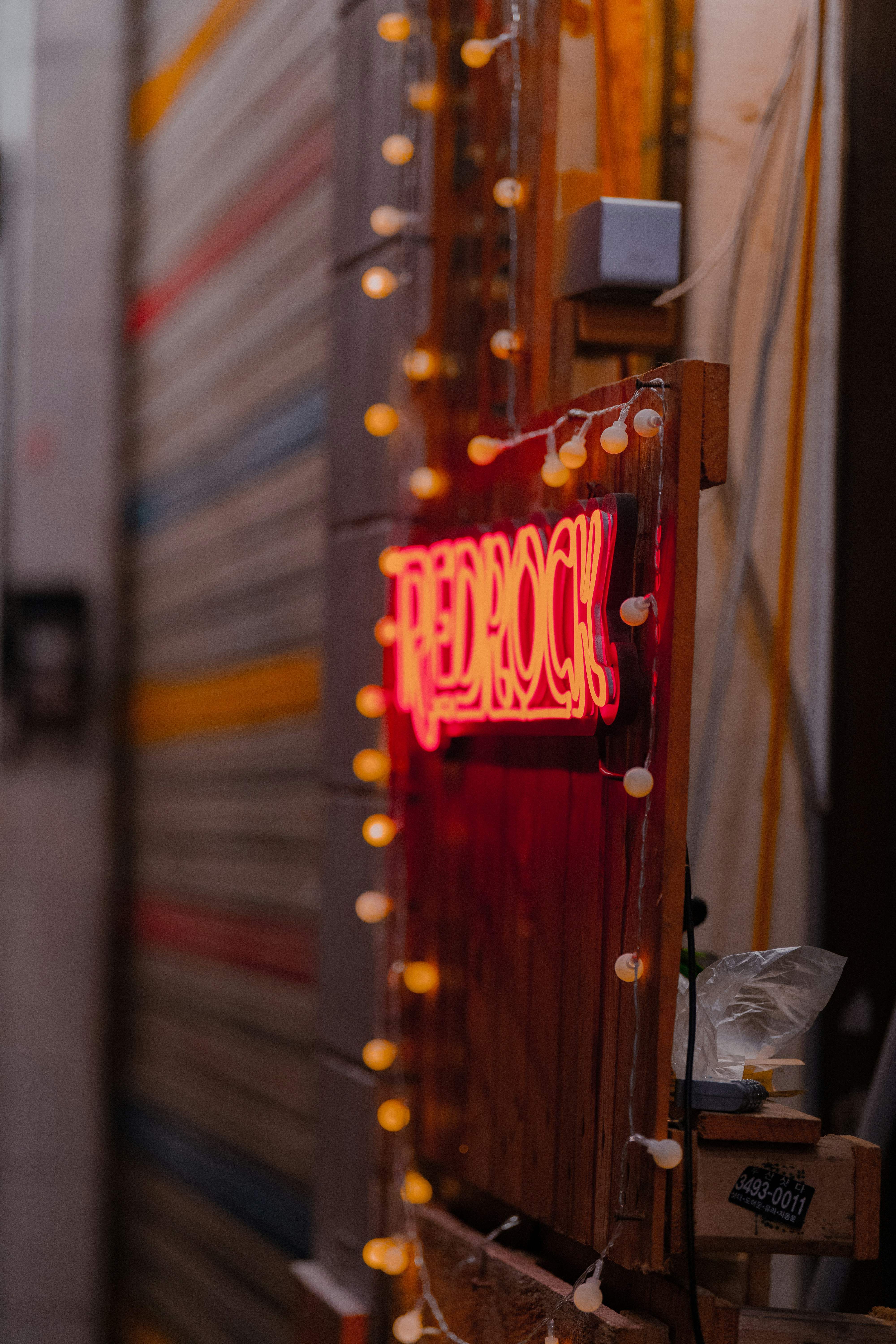 Red Neon on Weathered Wood Framed by Tiny Holiday Lights in an Alley