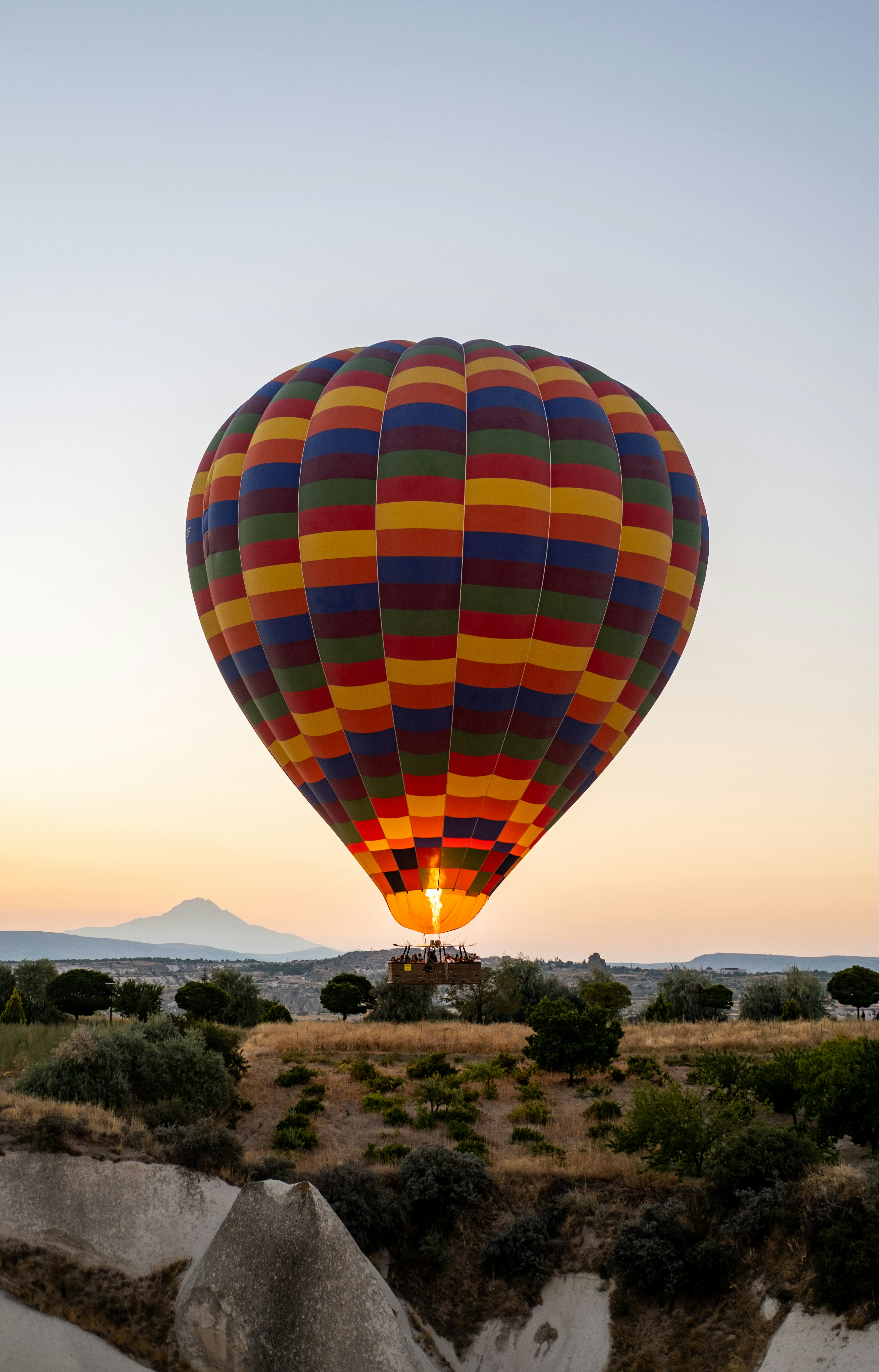 Rising Horizon: A Multicolored Balloon Adrift Over the Field