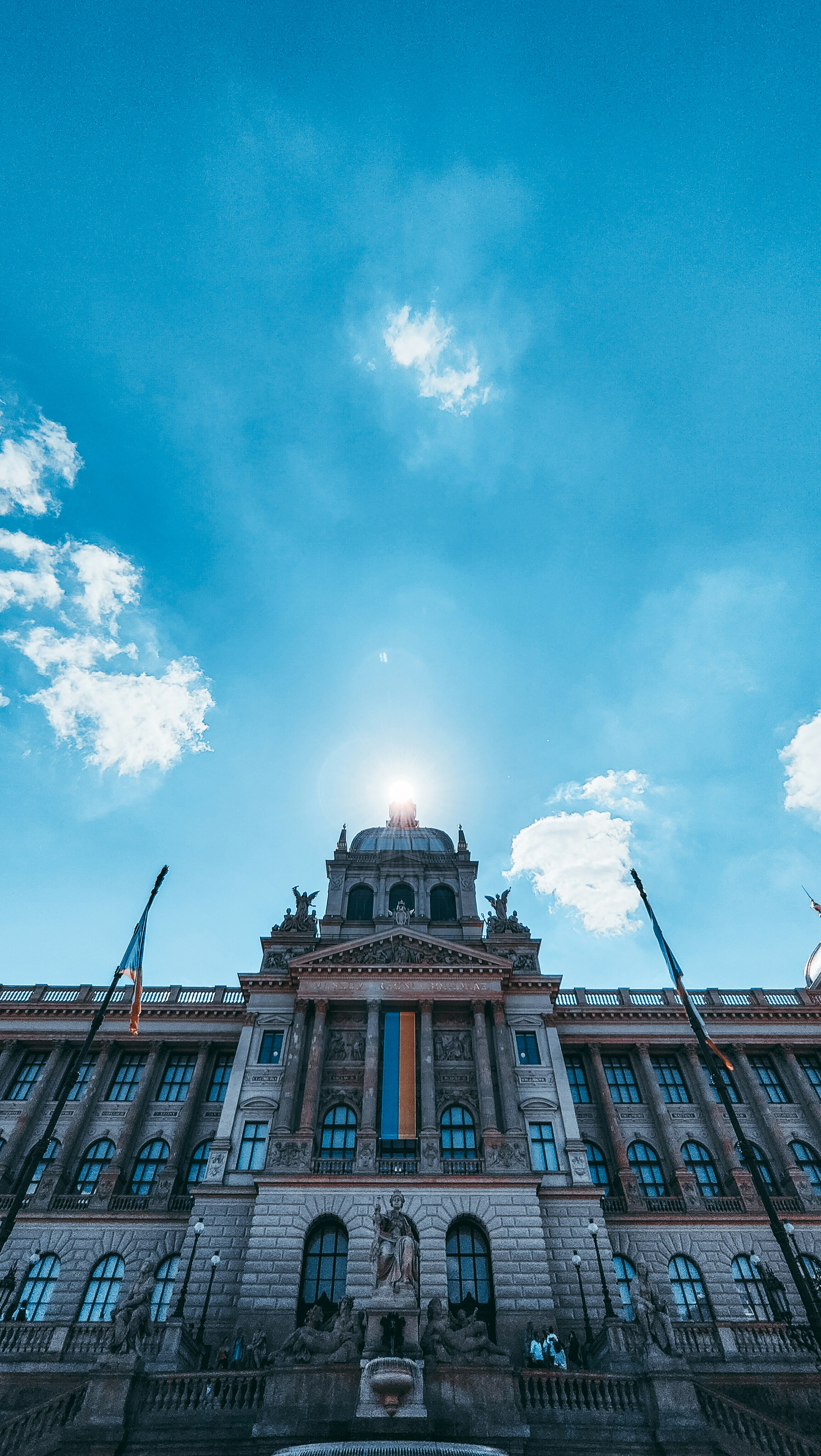 Sunflare Over the Grand Facade: A Neoclassical Building Framed by Cerulean Skies