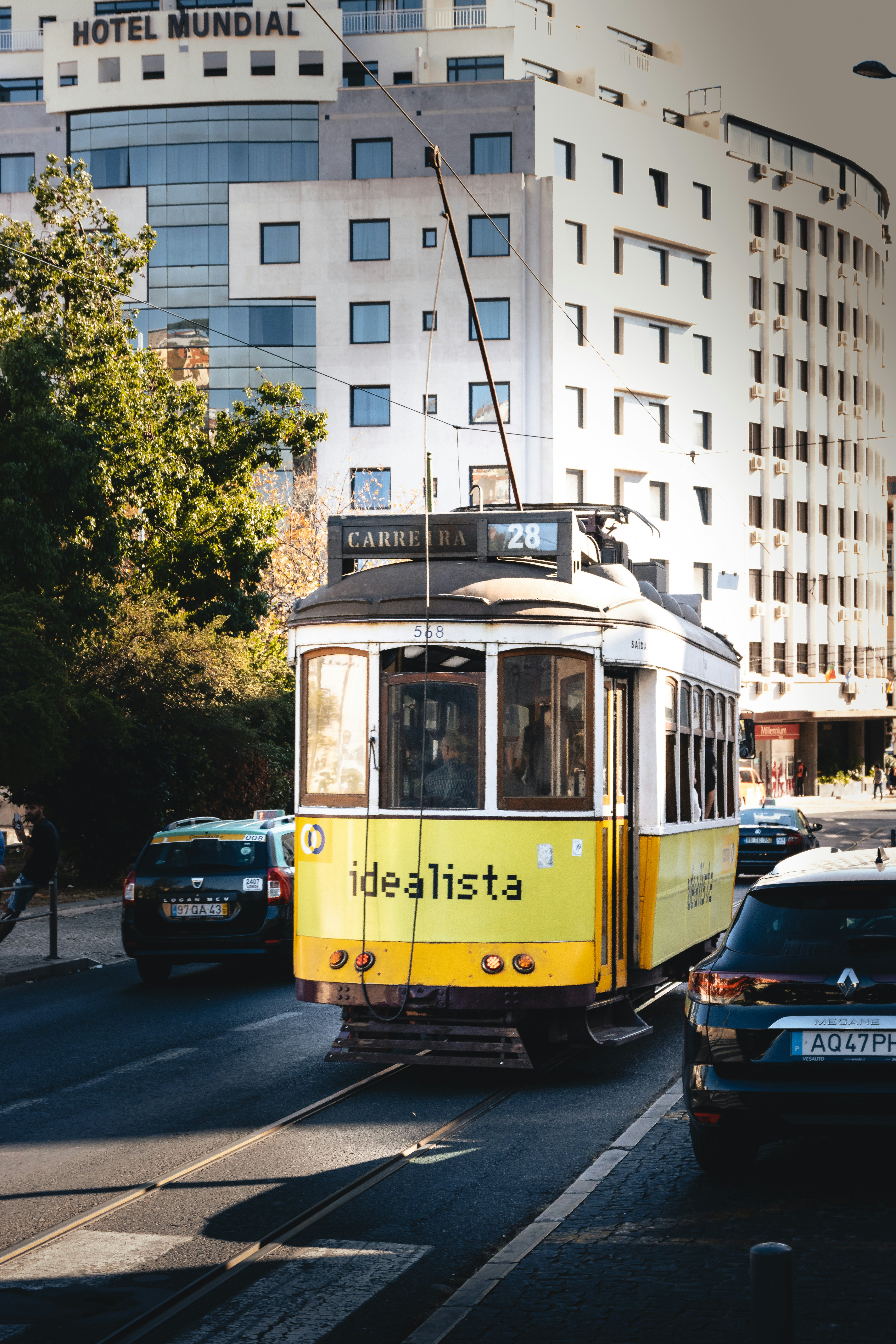 Yellow tram on a sunlit city street near modern buildings