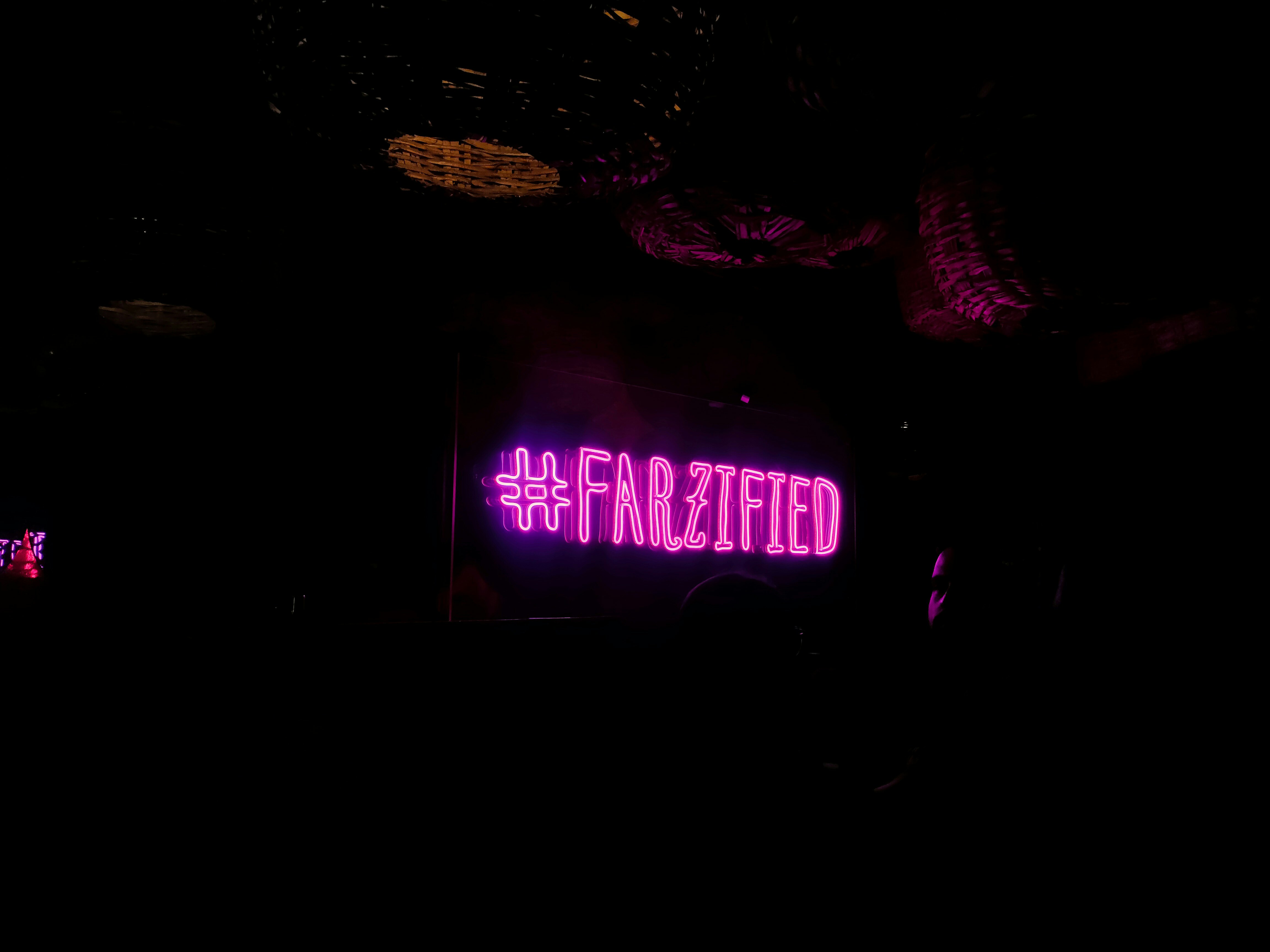 Illuminated hashtag '#FARZIFIED' in vibrant pink neon against a dark background, symbolizing modern digital culture.