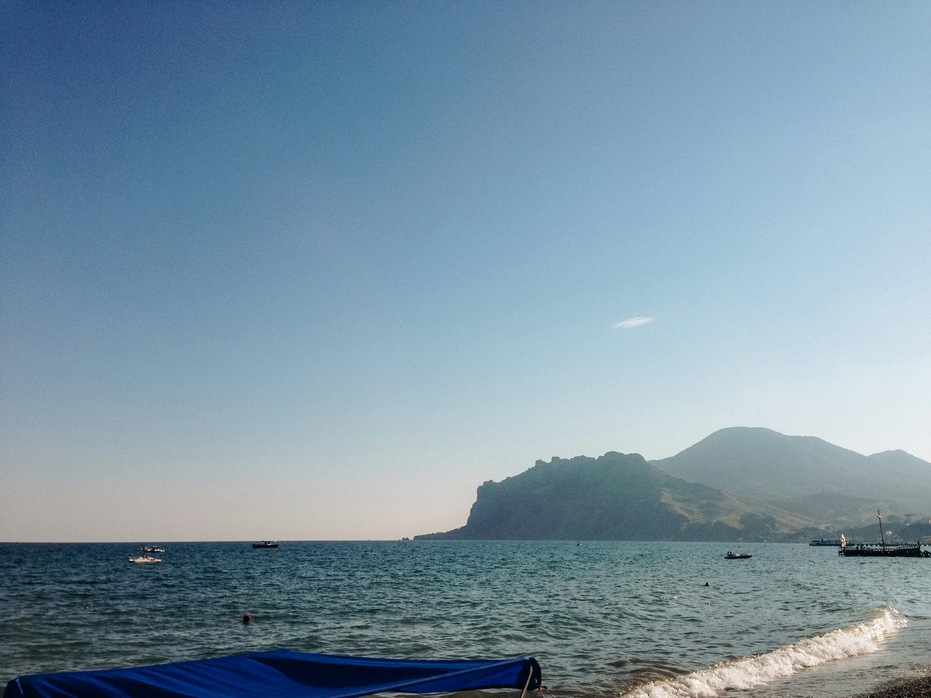 Una playa con barcos y una colina al fondo foto – Imagen de Agua ...