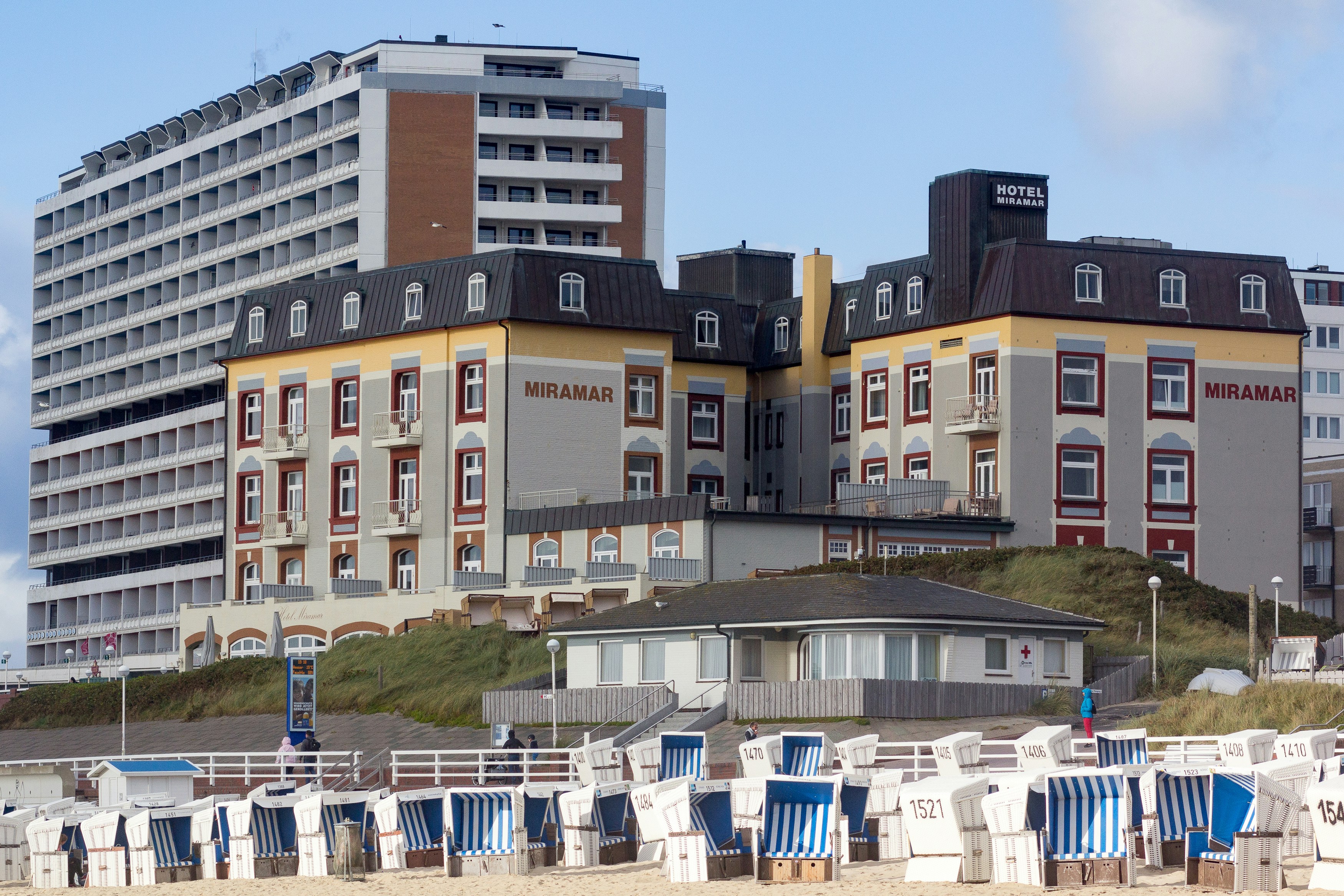 Seaside Hotel Complex Rising Above a Row of Beach Cabins