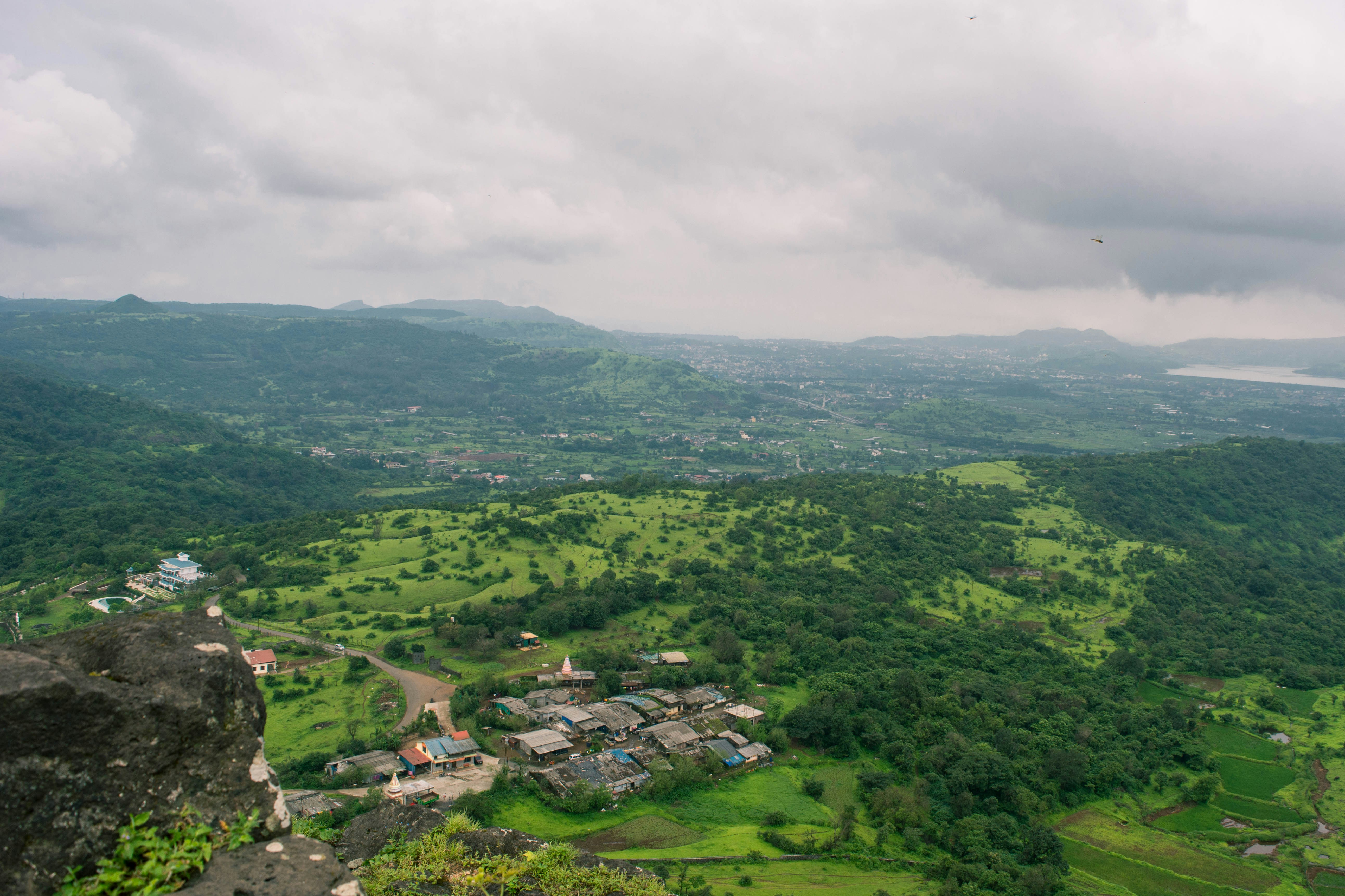 Green Mosaic: A Quiet Village Nestled in Rolling Hills Under Clouded Skies