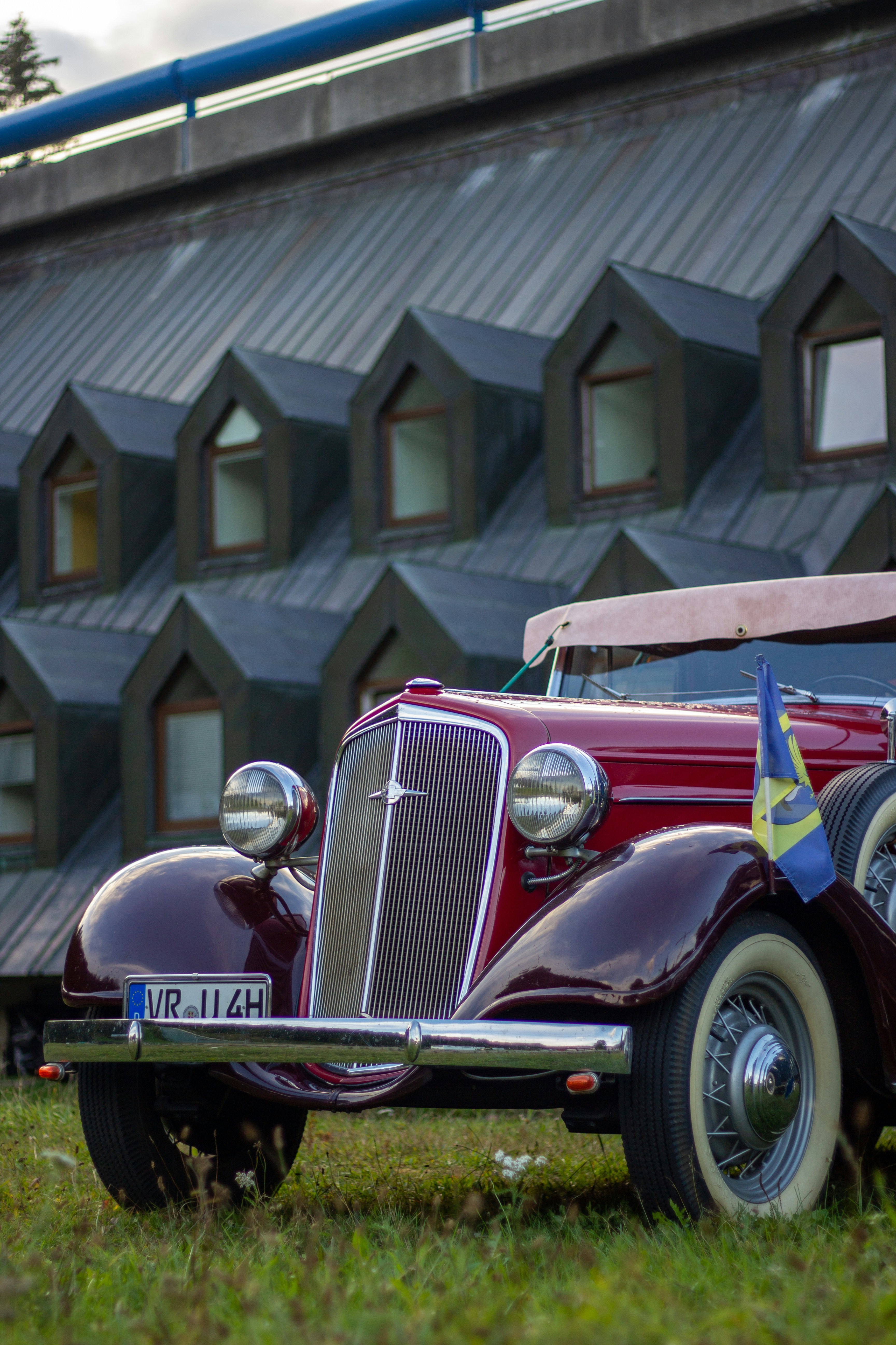 Crimson 1930s Roadster Before a Faceted Metal Facade