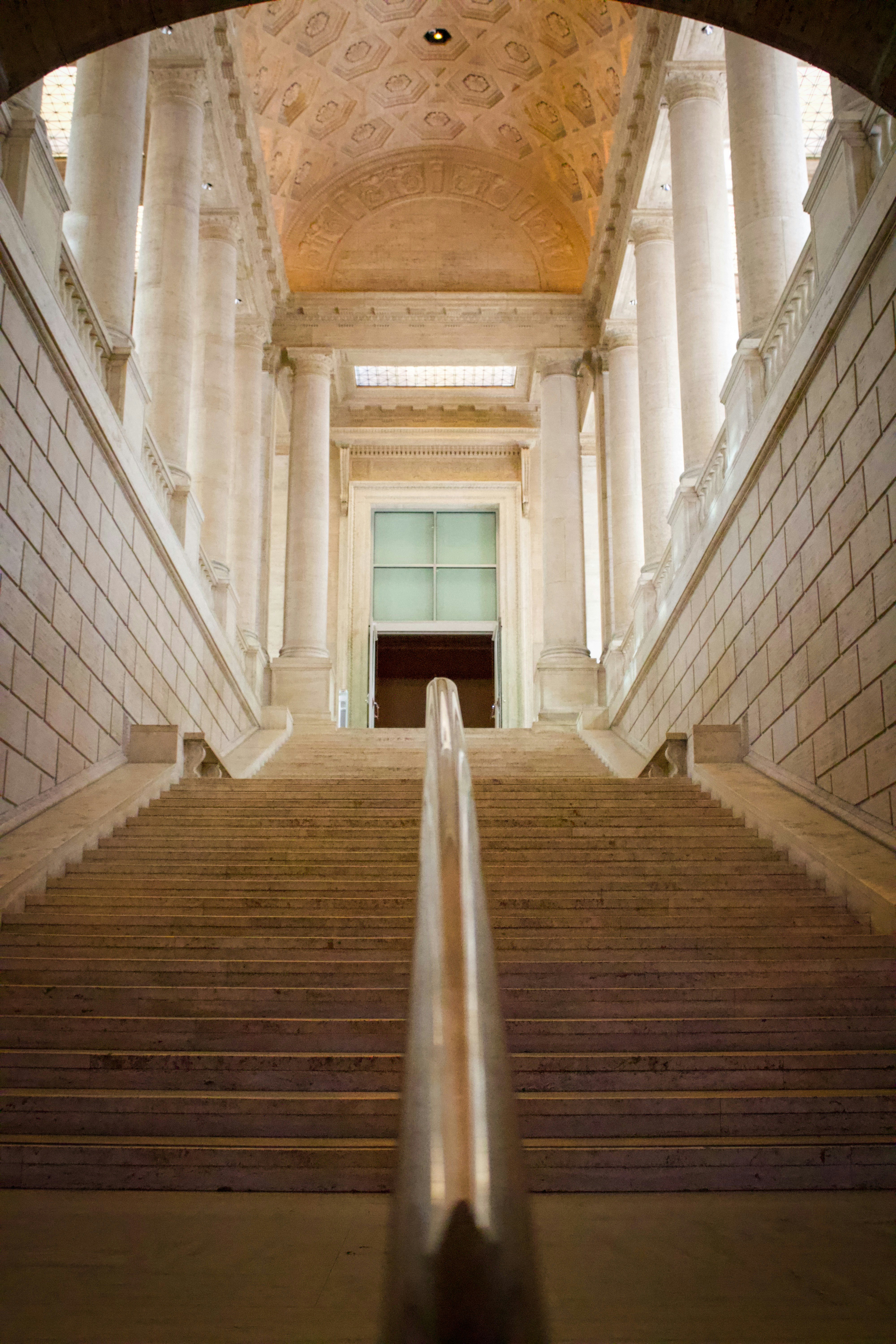 Elegant staircase leading to a grand entrance, framed by towering columns and intricate ceiling details.