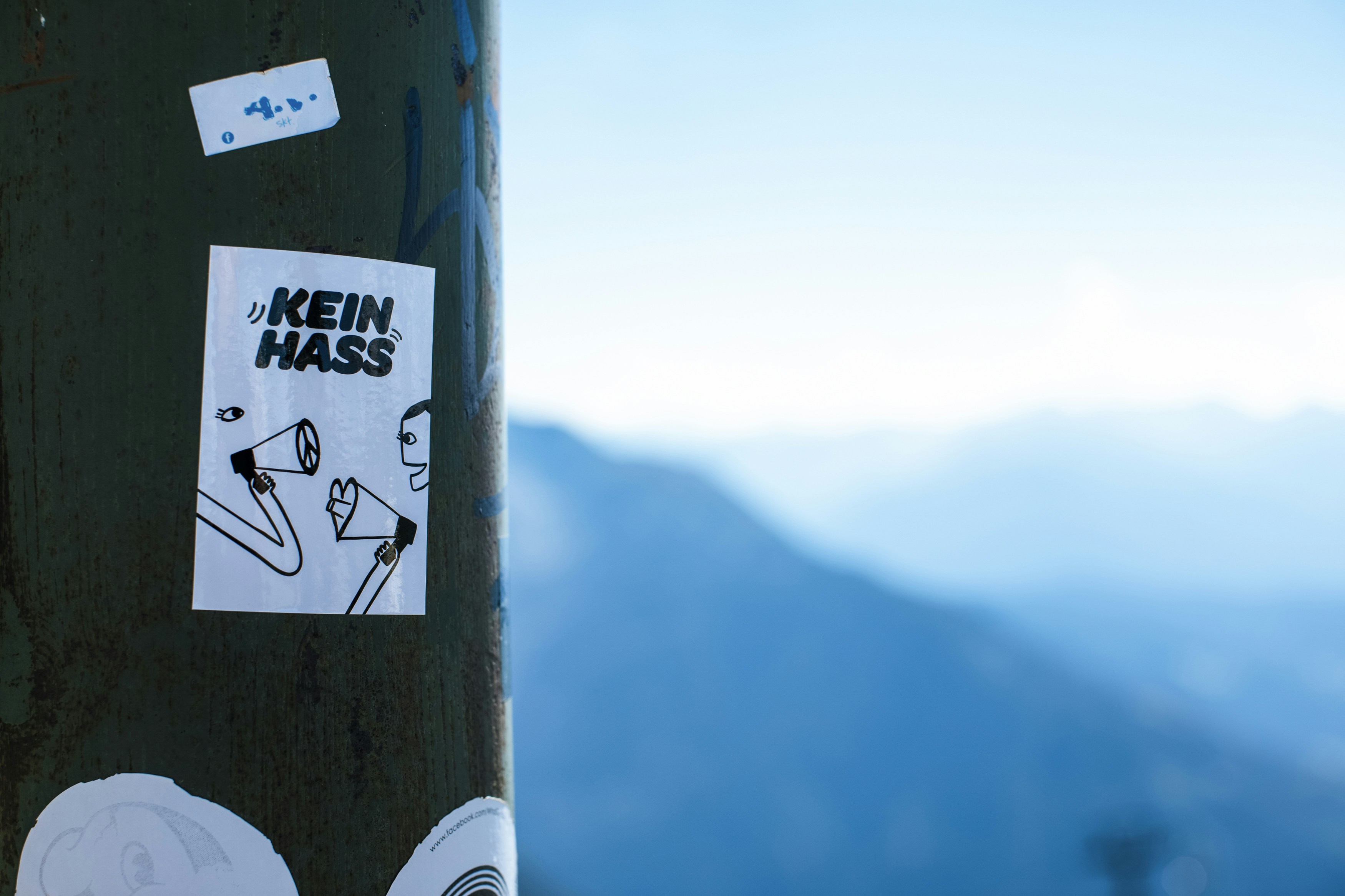 Kein Hass on the Alpine Pole: A Sticker Stands Quiet Against Blue Mist