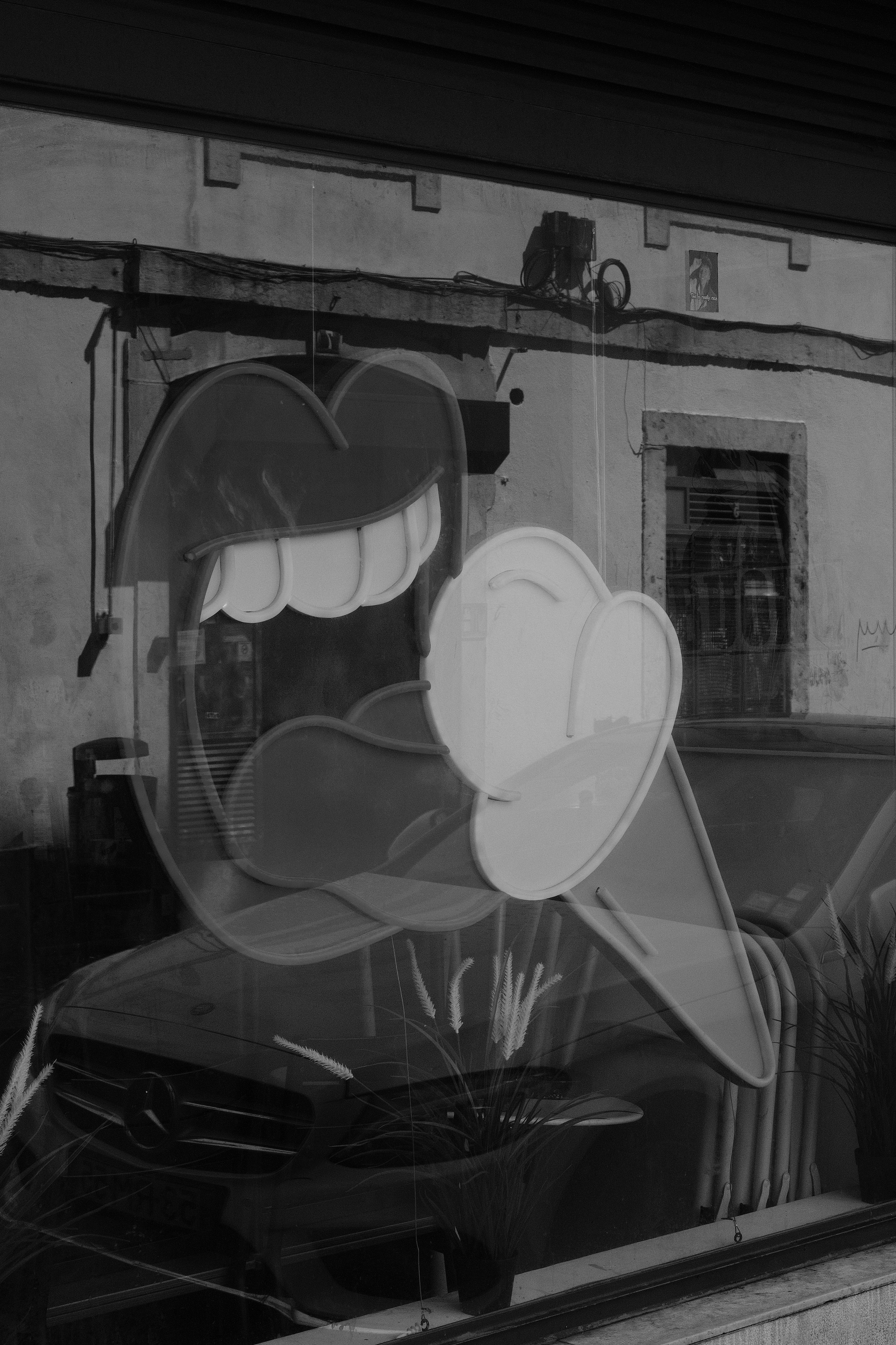 Neon Grin Reflected: A Window Portrait in Monochrome