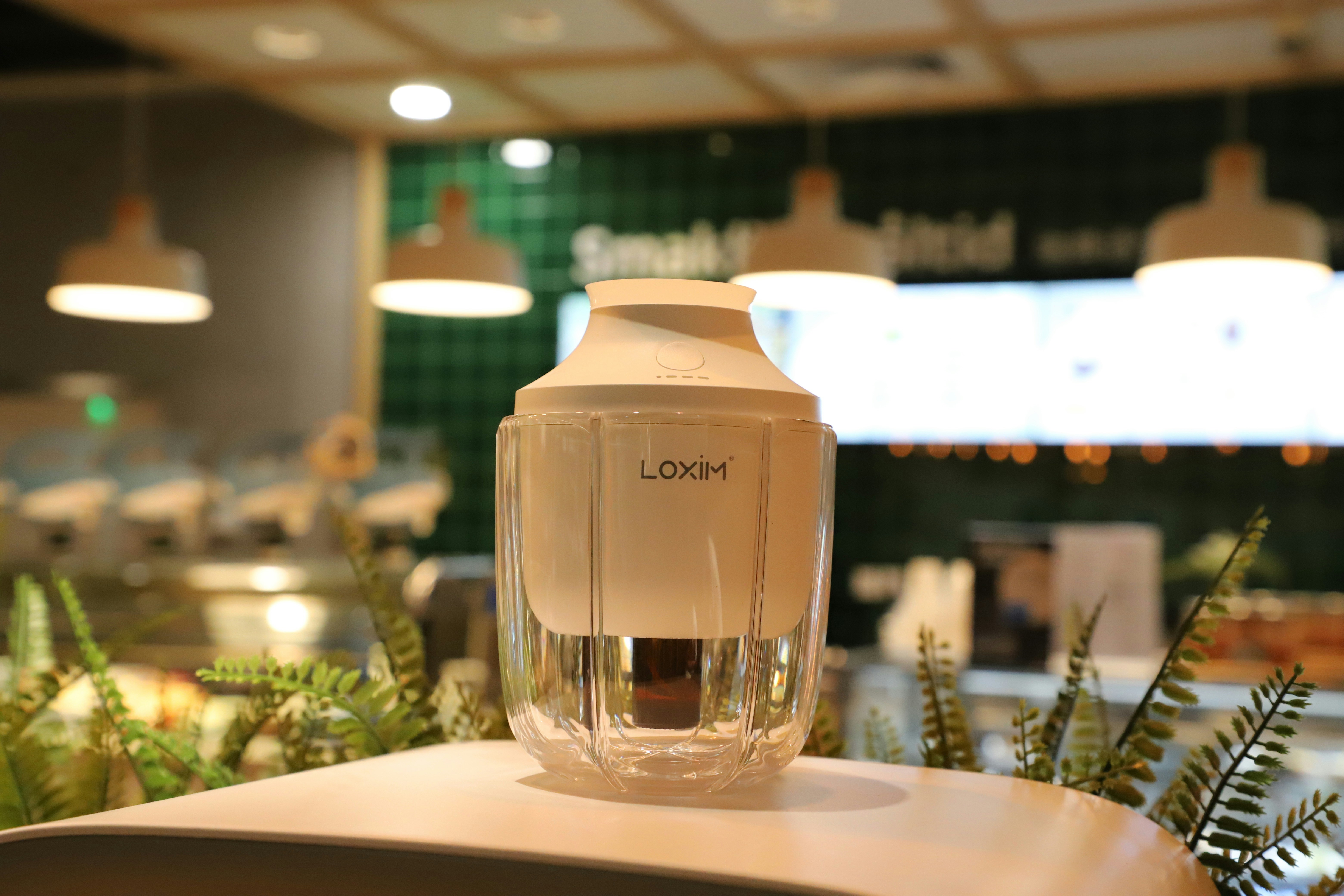 Sleek Loxim device elegantly displayed against a vibrant backdrop in a contemporary setting. Its design reflects modern culinary technology.