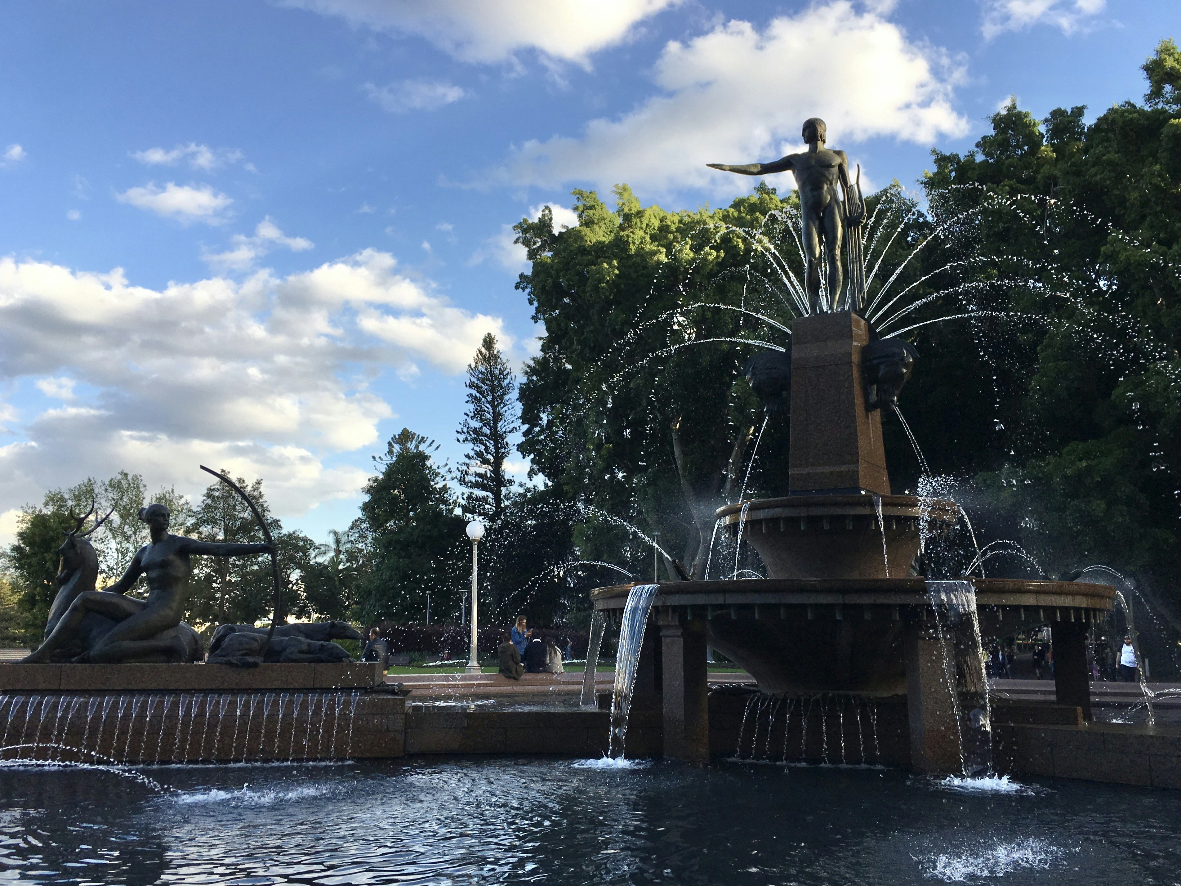 Arcs of Water Embrace the Central Bronze Fountain in a Sunlit Park