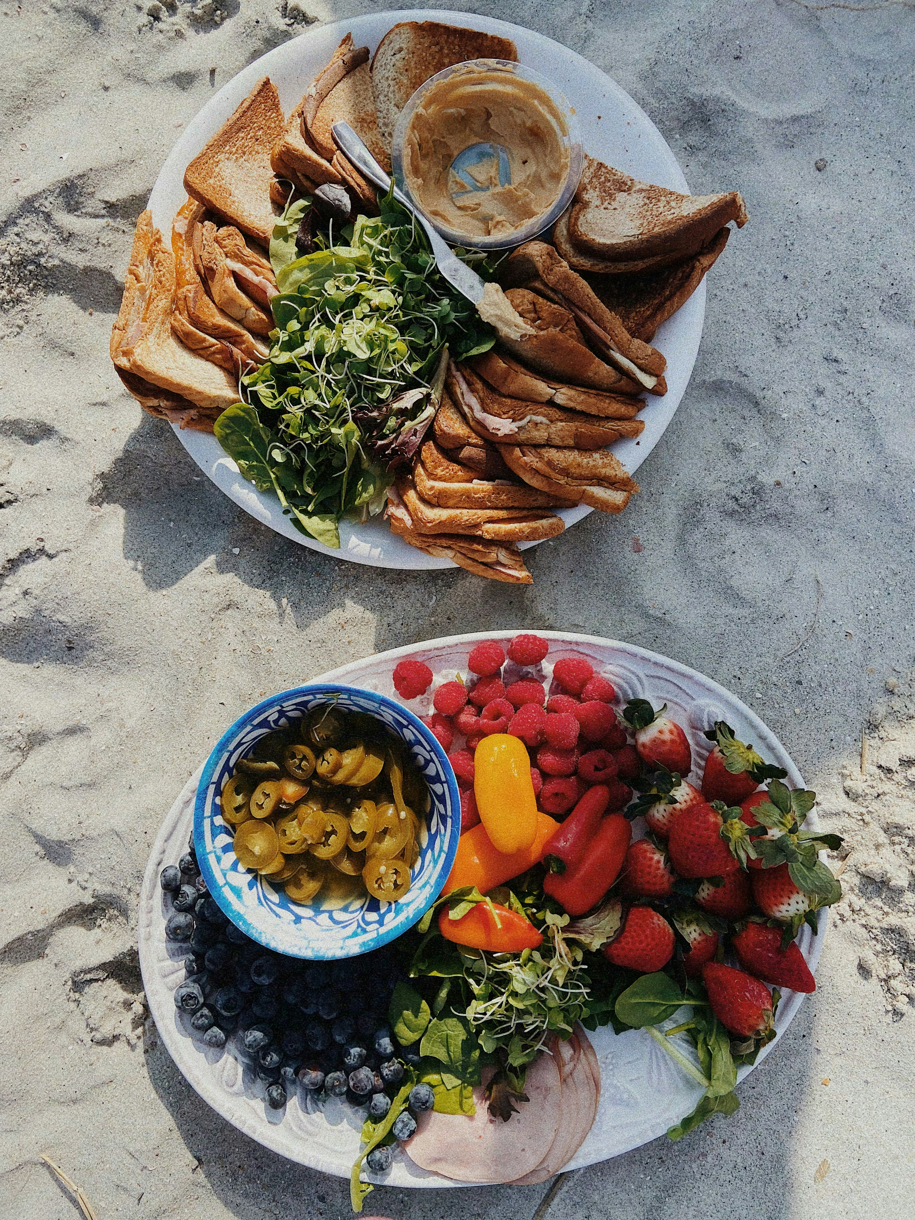 Shoreline Feast: Twin Plates of Toast and Colorful Fruit on Sand