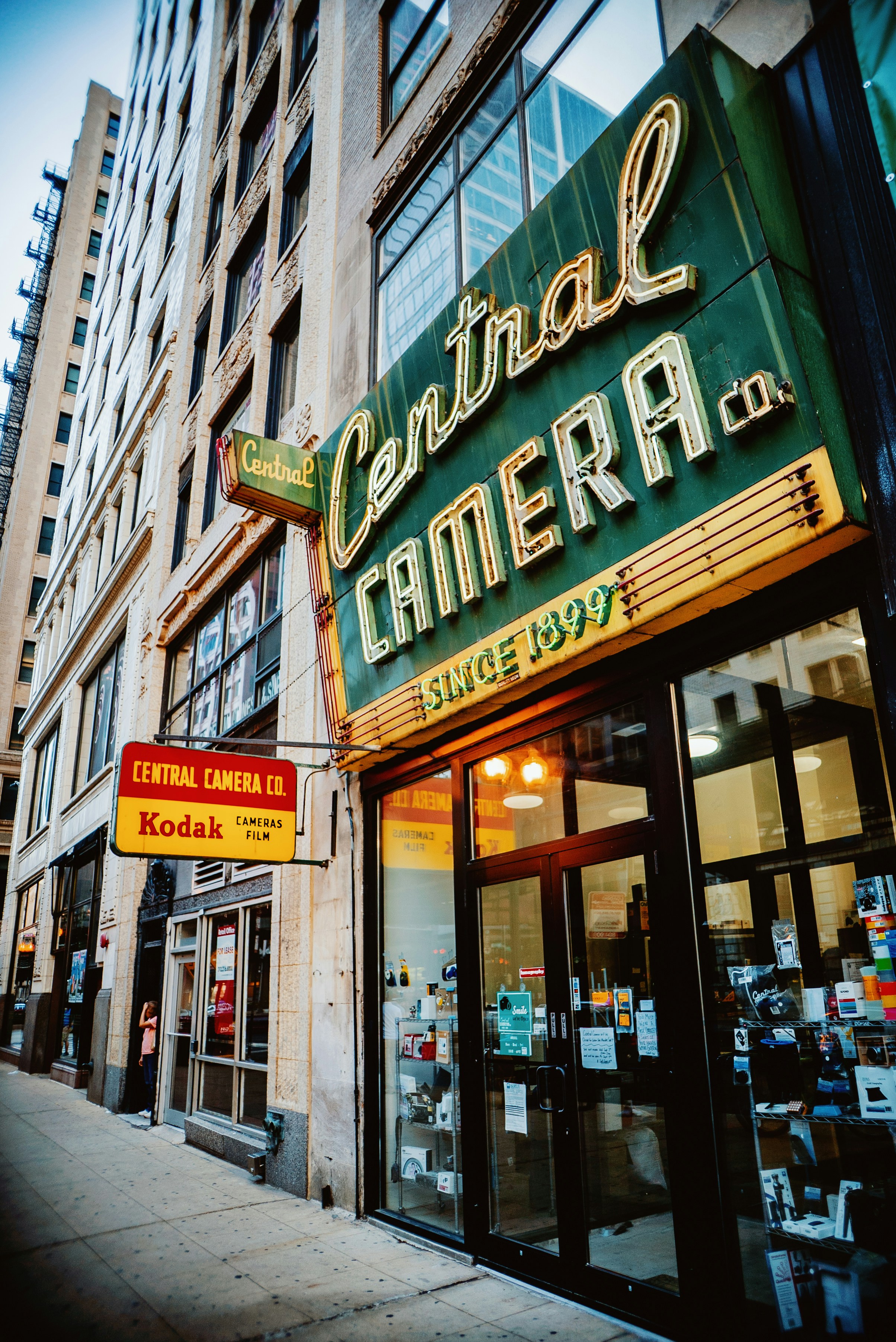 Neon Script Over Central Camera Co.: A Vintage Shop on a Busy City Block