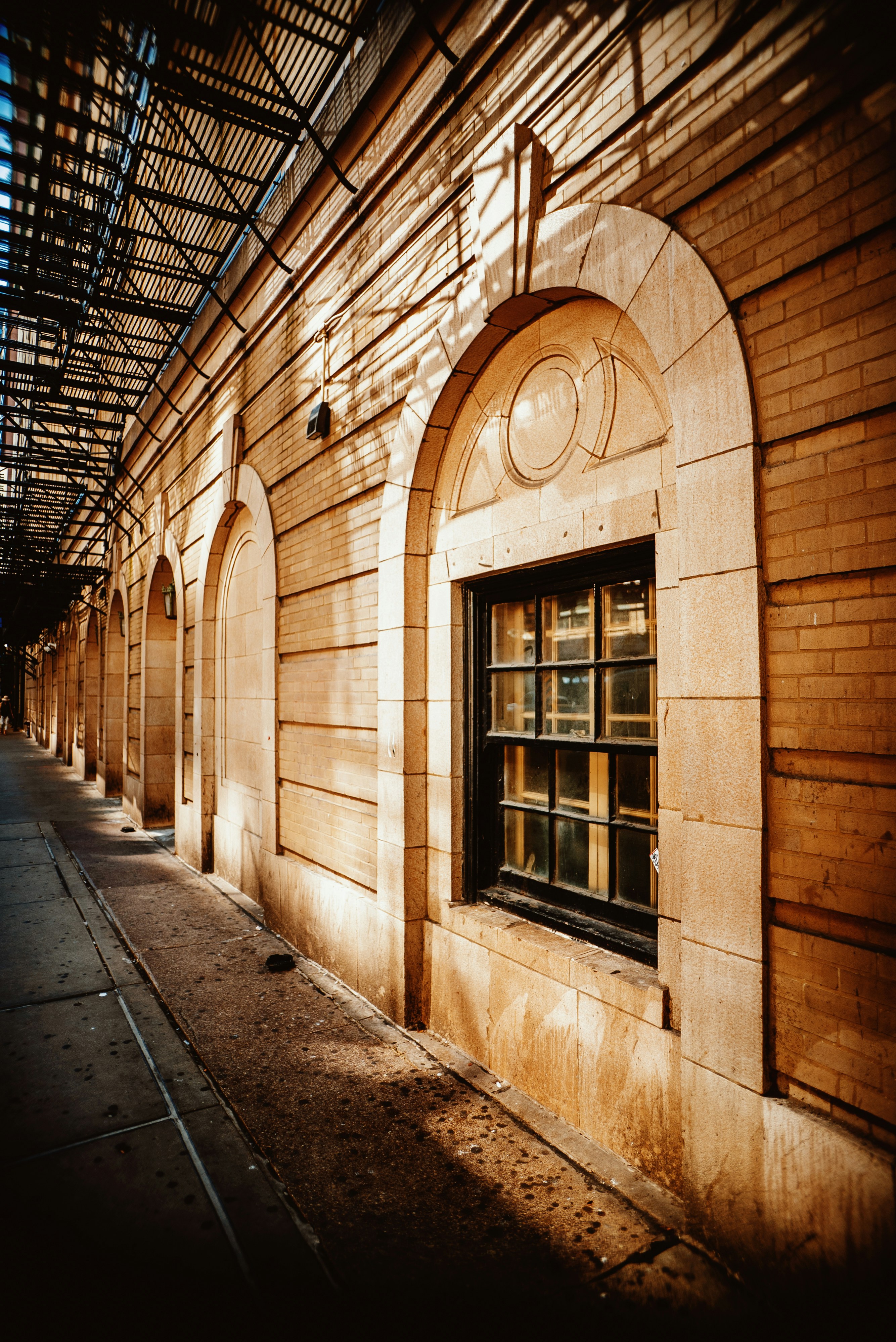 Sunlit Archway Corridor: Brick and Windowed Facade Along a Quiet Alley