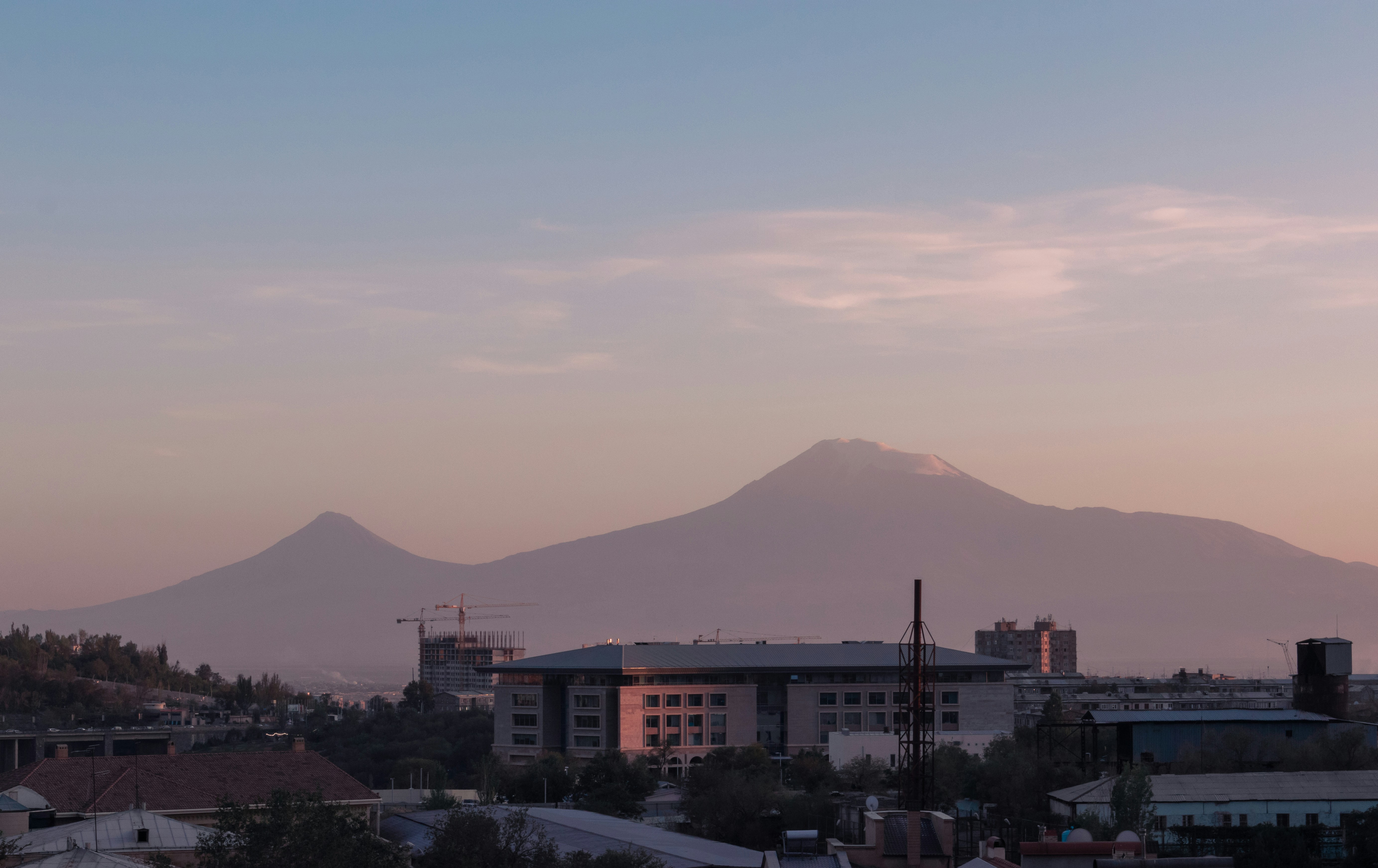 Dusk Over Suburban Ridge: Twin Volcano Silhouettes Behind a Quiet Cityscape