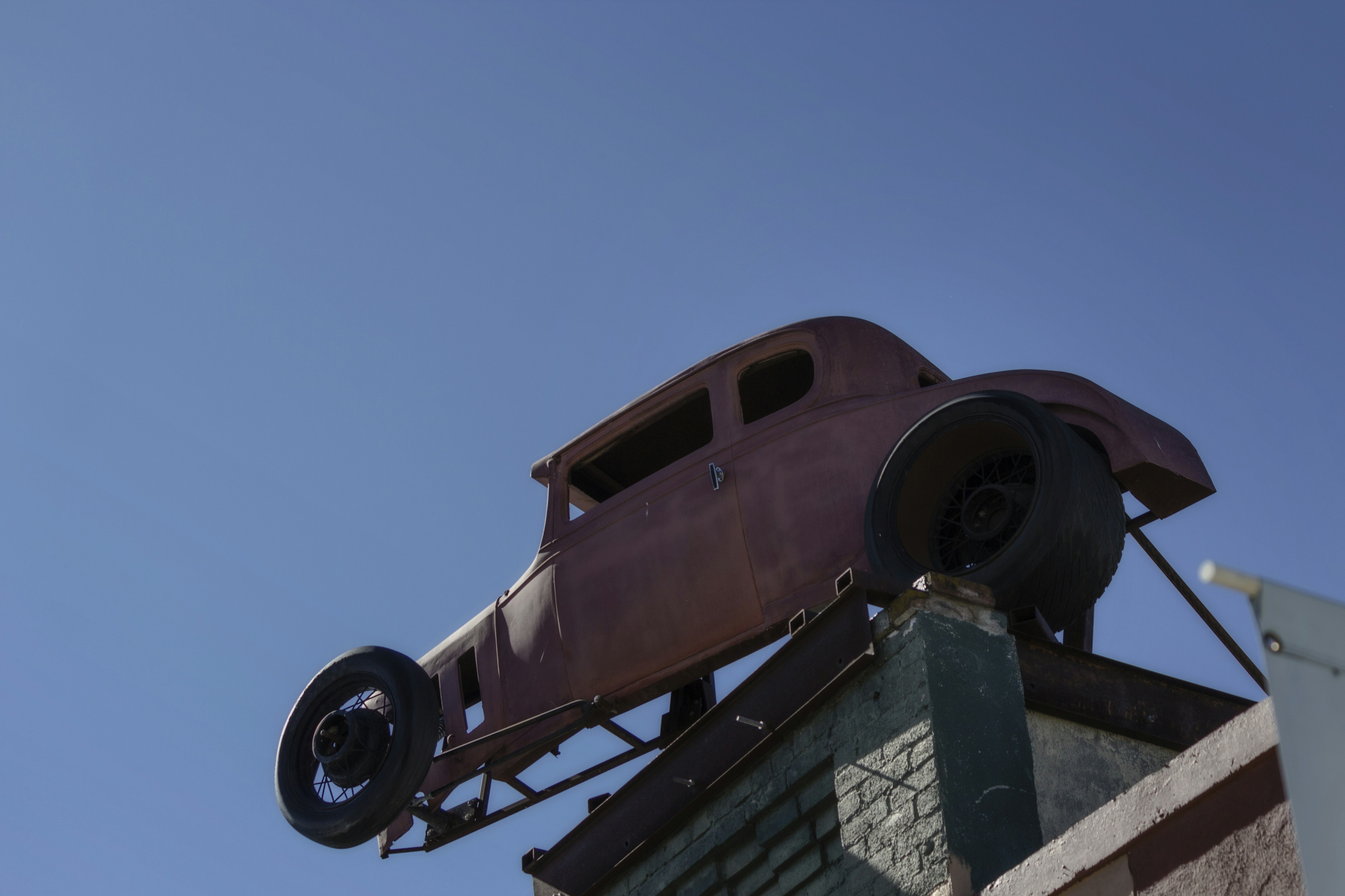 Rusted Vintage Car Balancing atop a Weathered Pillar