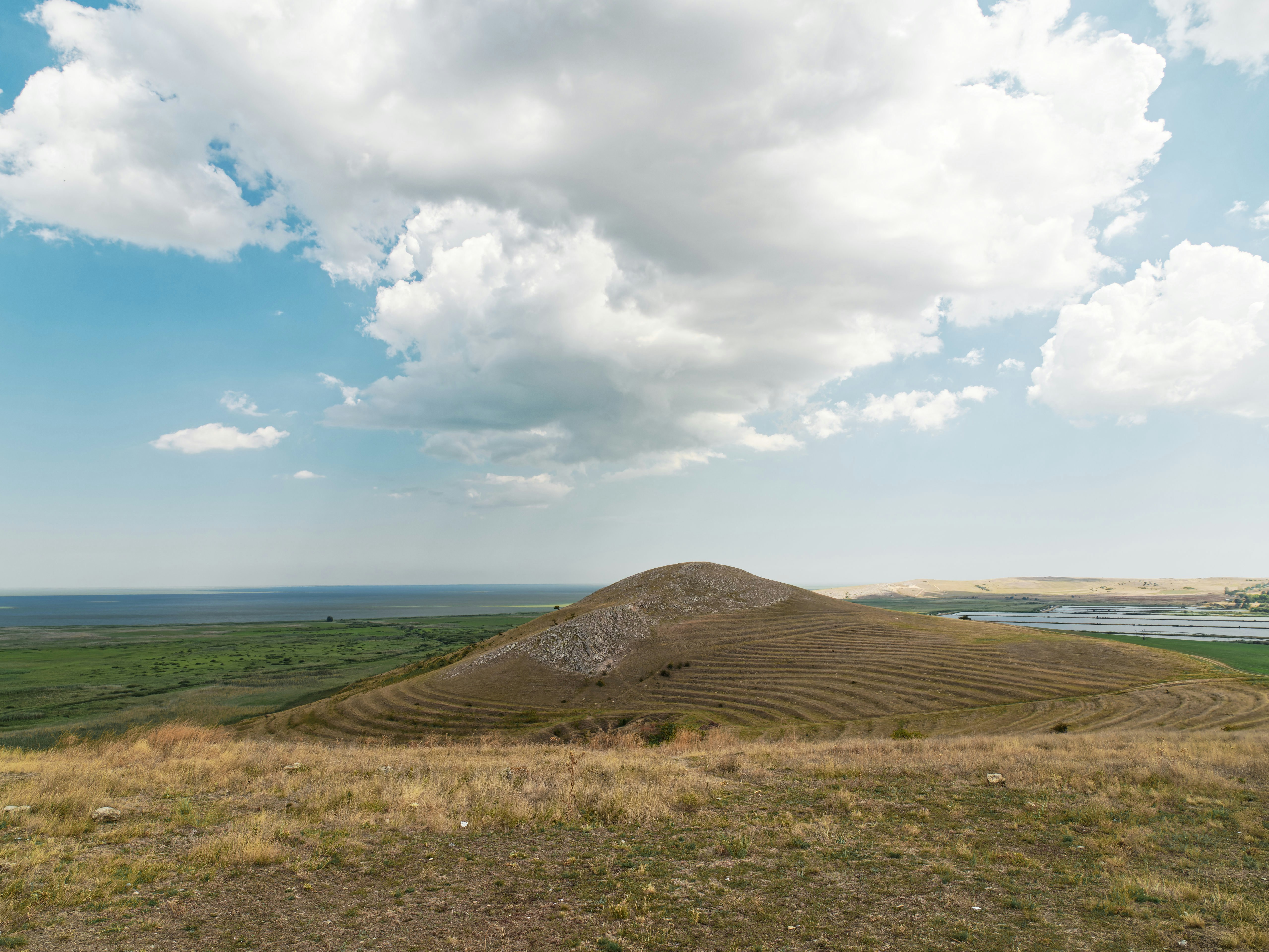 A large hill with a body of water in the background photo – Free ...
