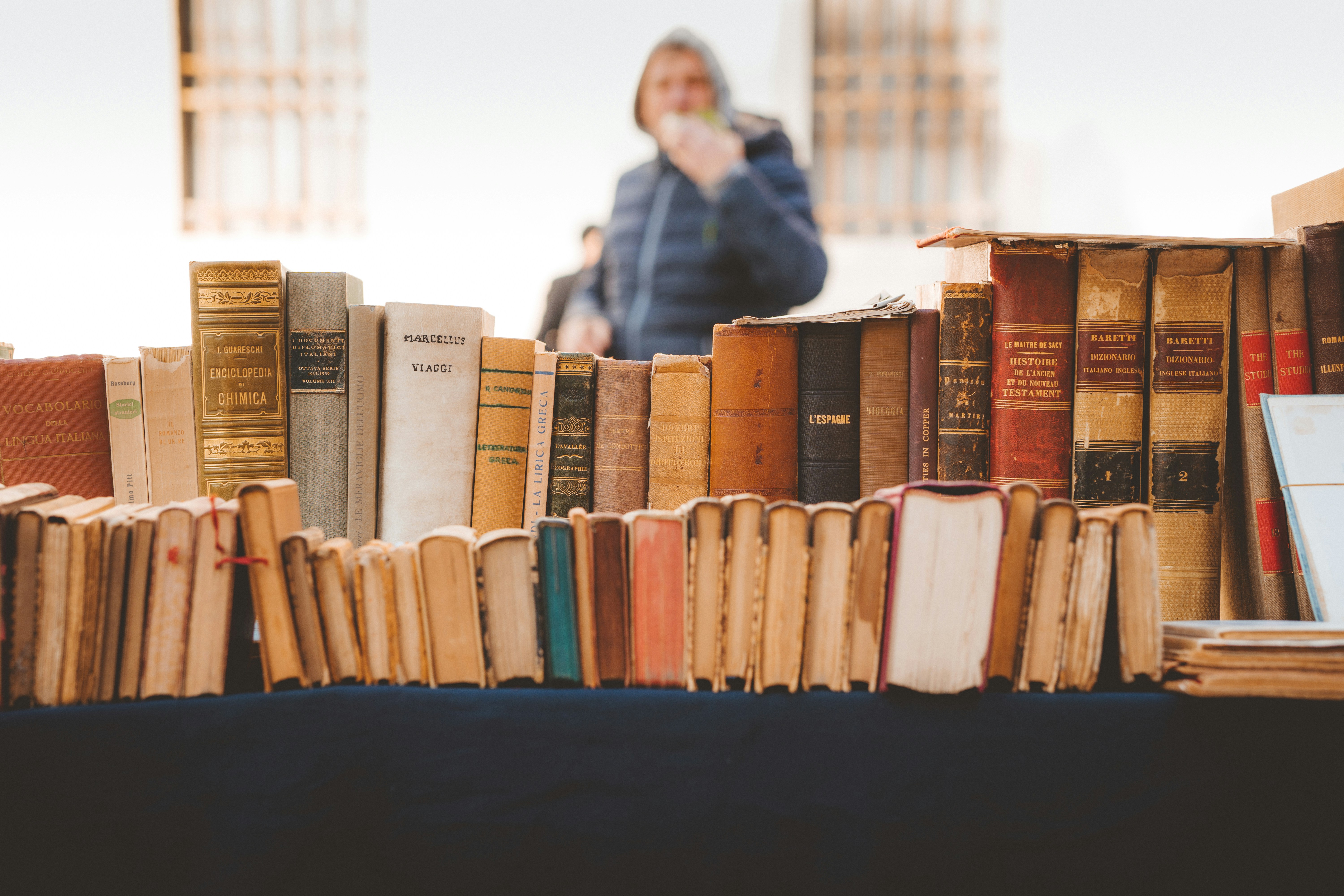 A person standing behind a table with books on it photo – Free Italy ...