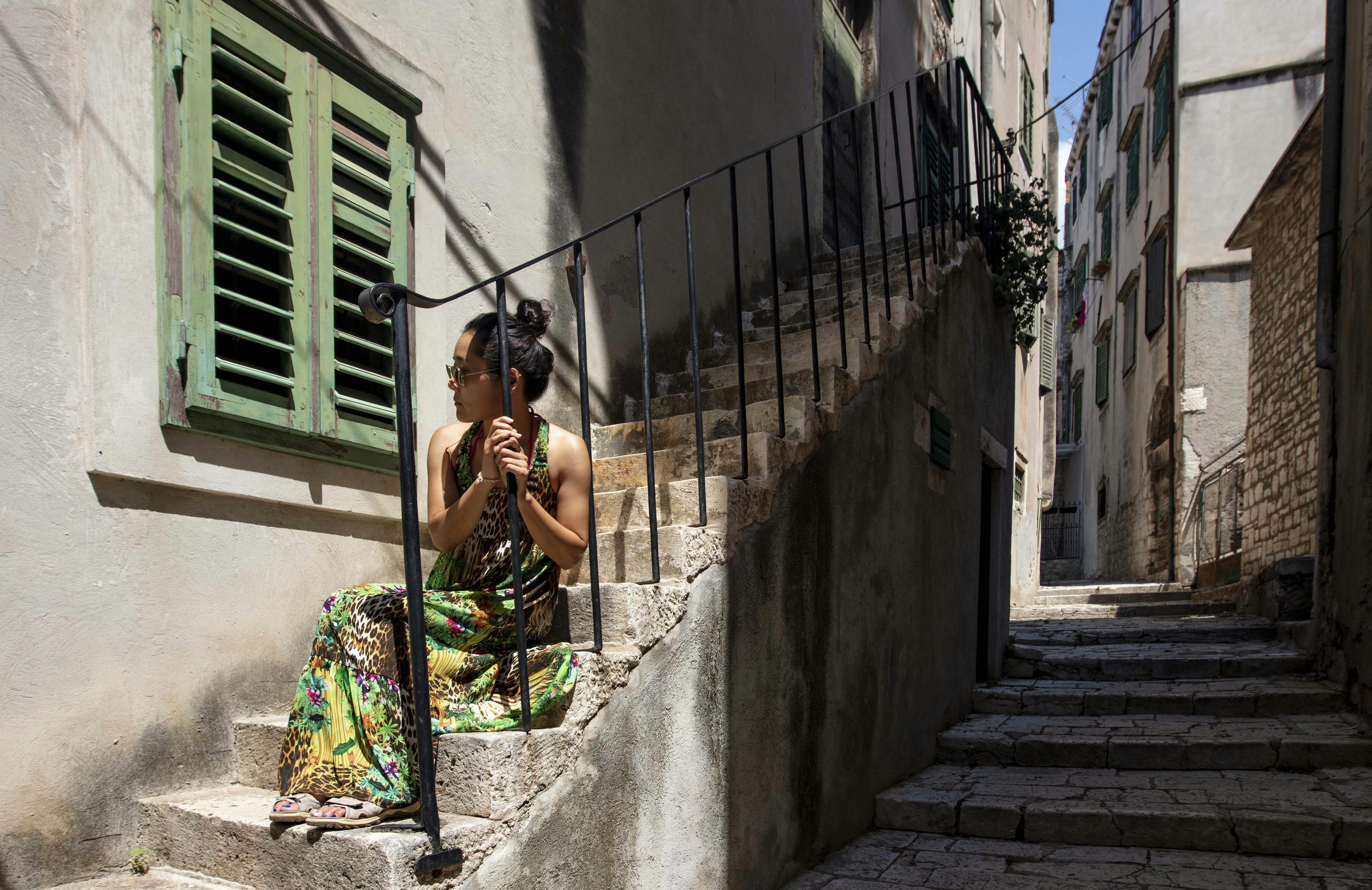 Sunlit Steps and Verdant Dress: A Quiet Street Portrait on Stone Staircase