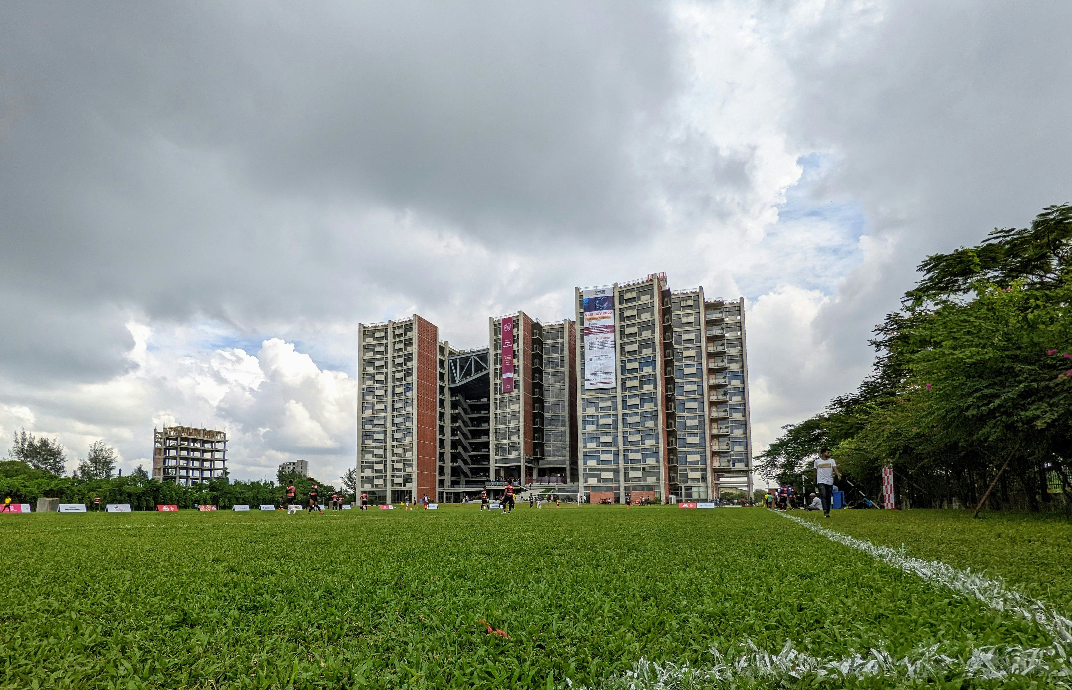 Modern building complex surrounded by lush green grass and cloudy skies, illustrating a harmonious blend of architecture and nature.