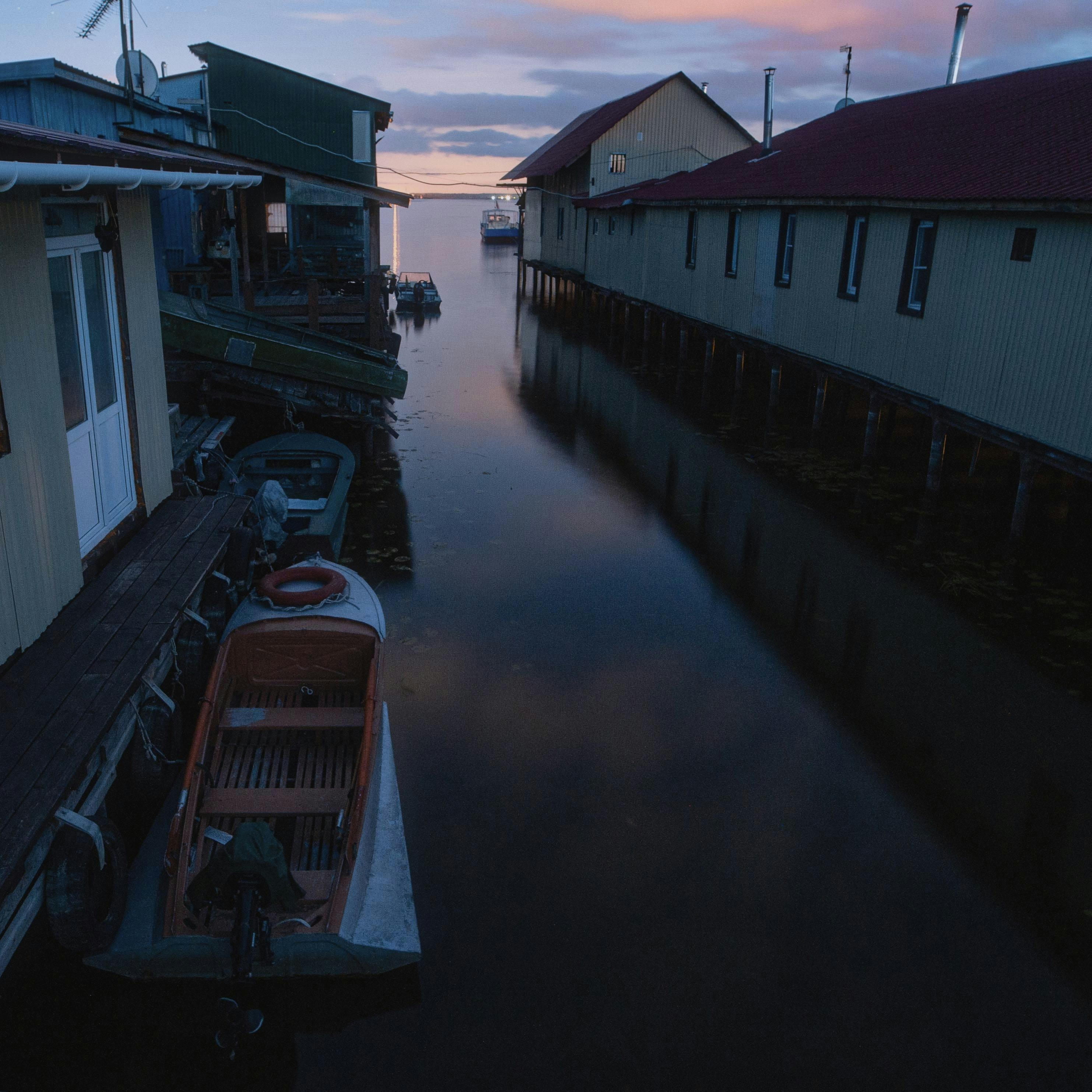 Quiet Marina Corridor: Boats and Warehouses Framing a Sunset Canal