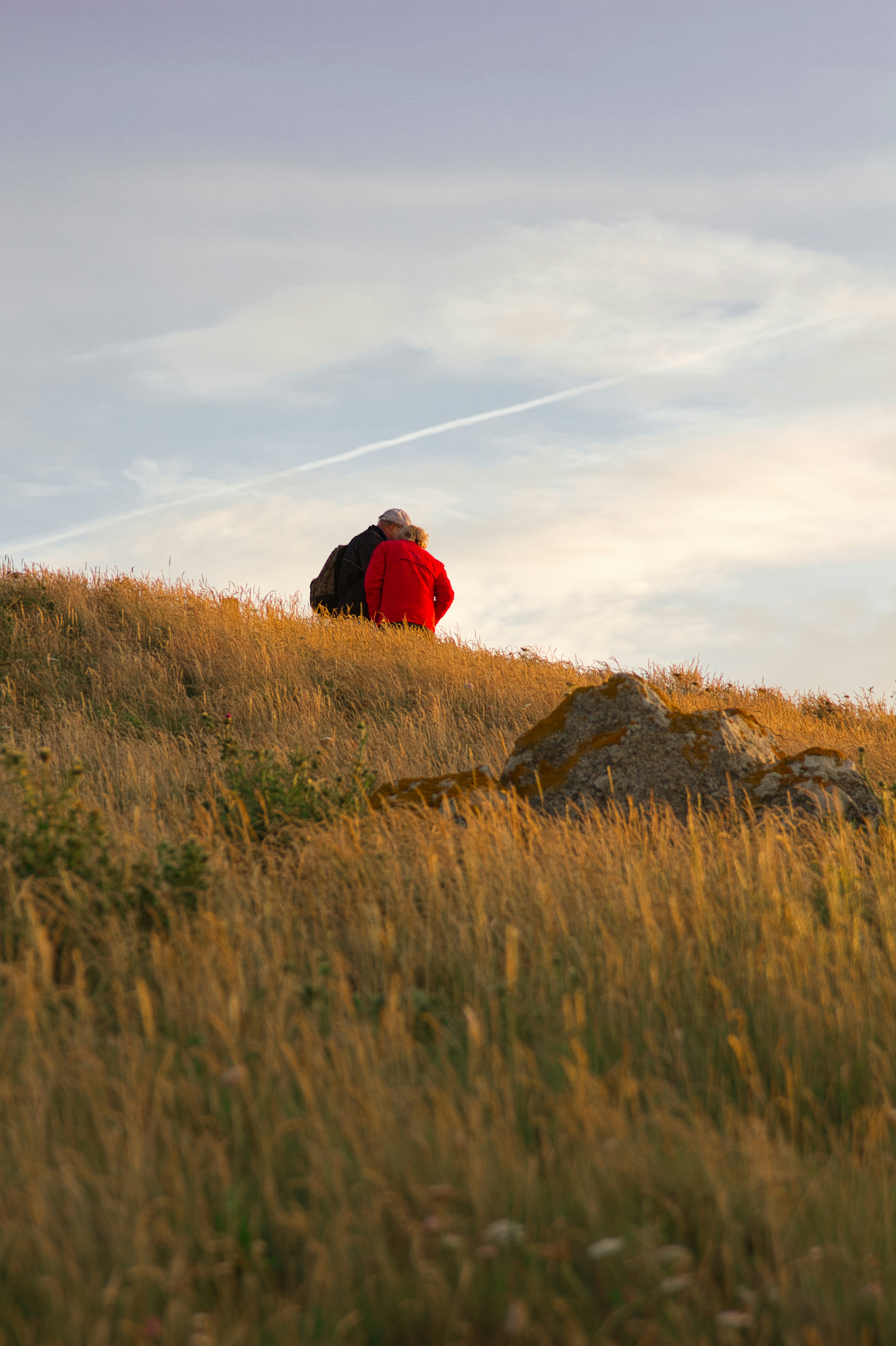 Two Figures in Red Climb the Golden Slope at Sunset
