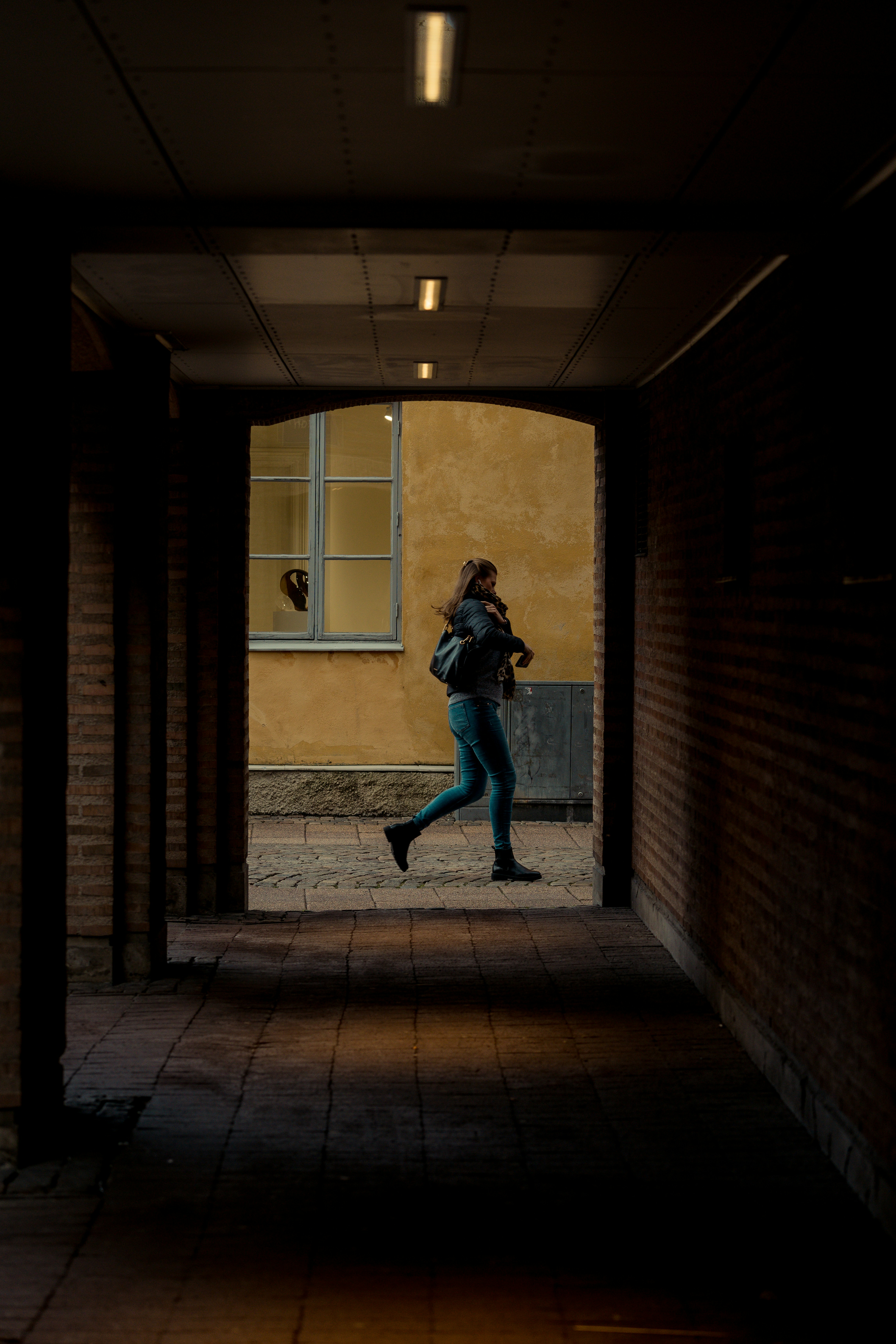 Through the Arch to Daylight: A lone traveler steps from shadow into a sunlit courtyard