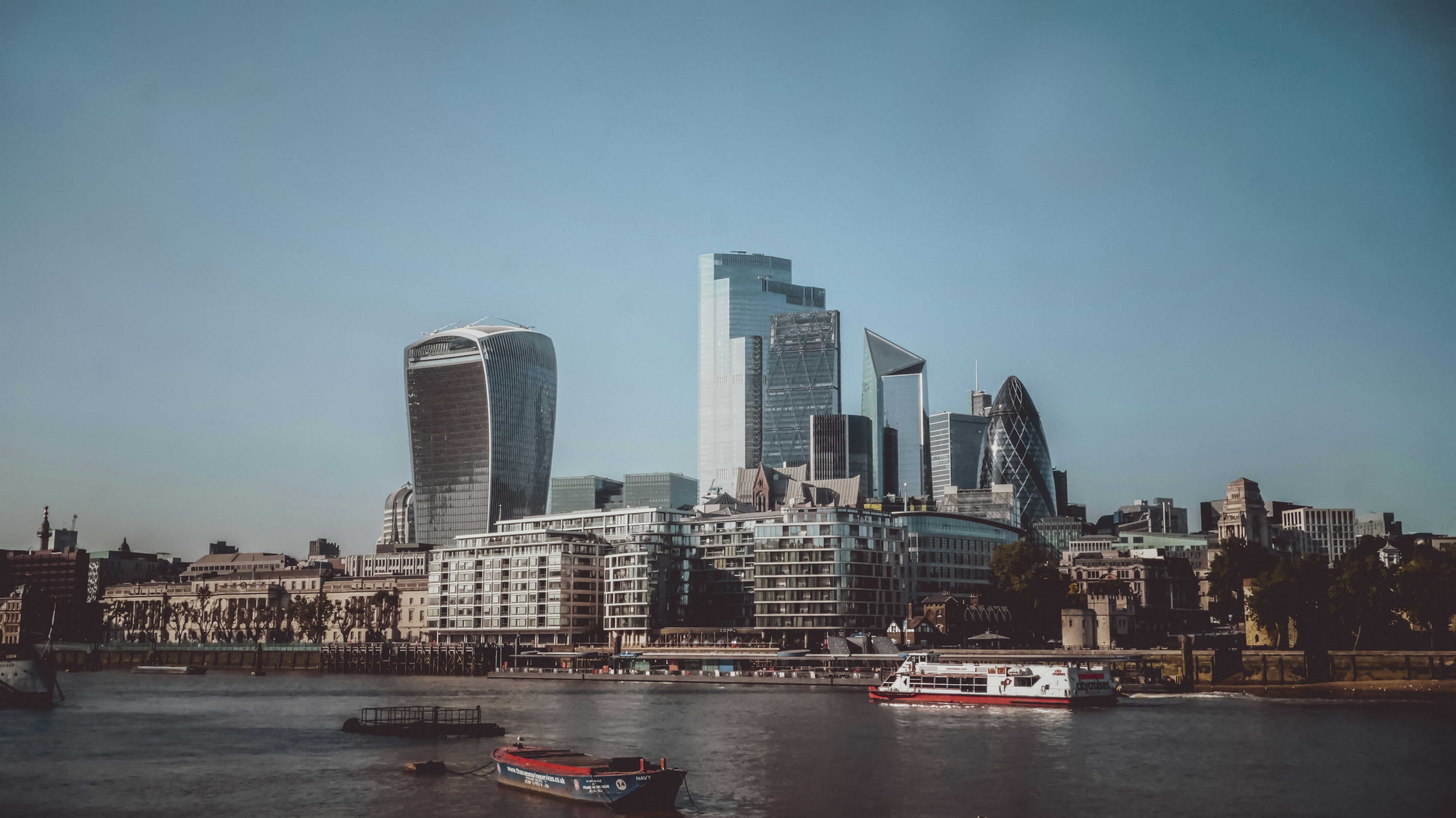 Contemporary skyscrapers lining the river with a clear blue sky.