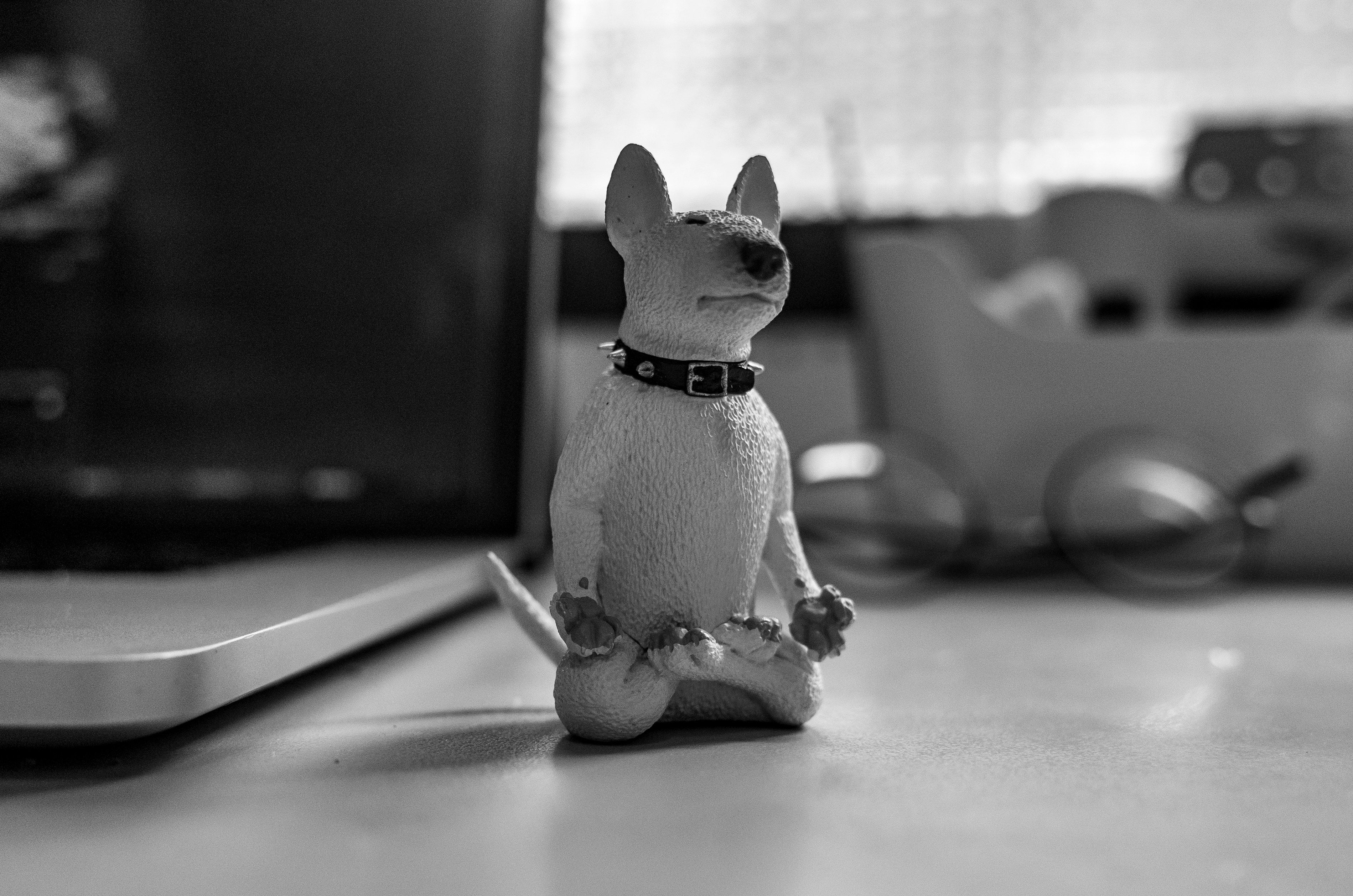 Backlit Desk Idol: A Tiny Cat-Dog Figurine in Quiet Focus