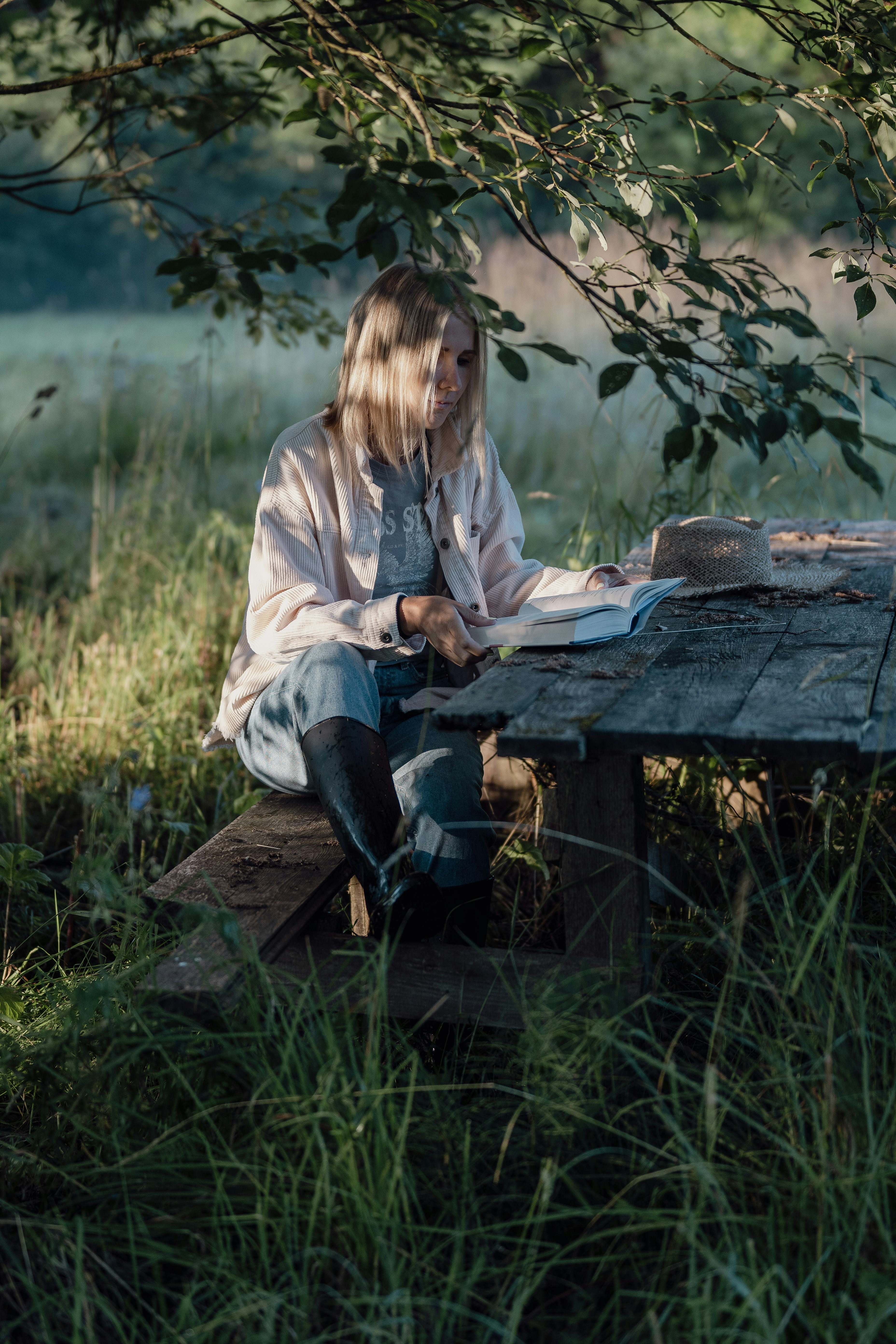 A person sitting on a bench reading a book photo – Free Green Image on ...