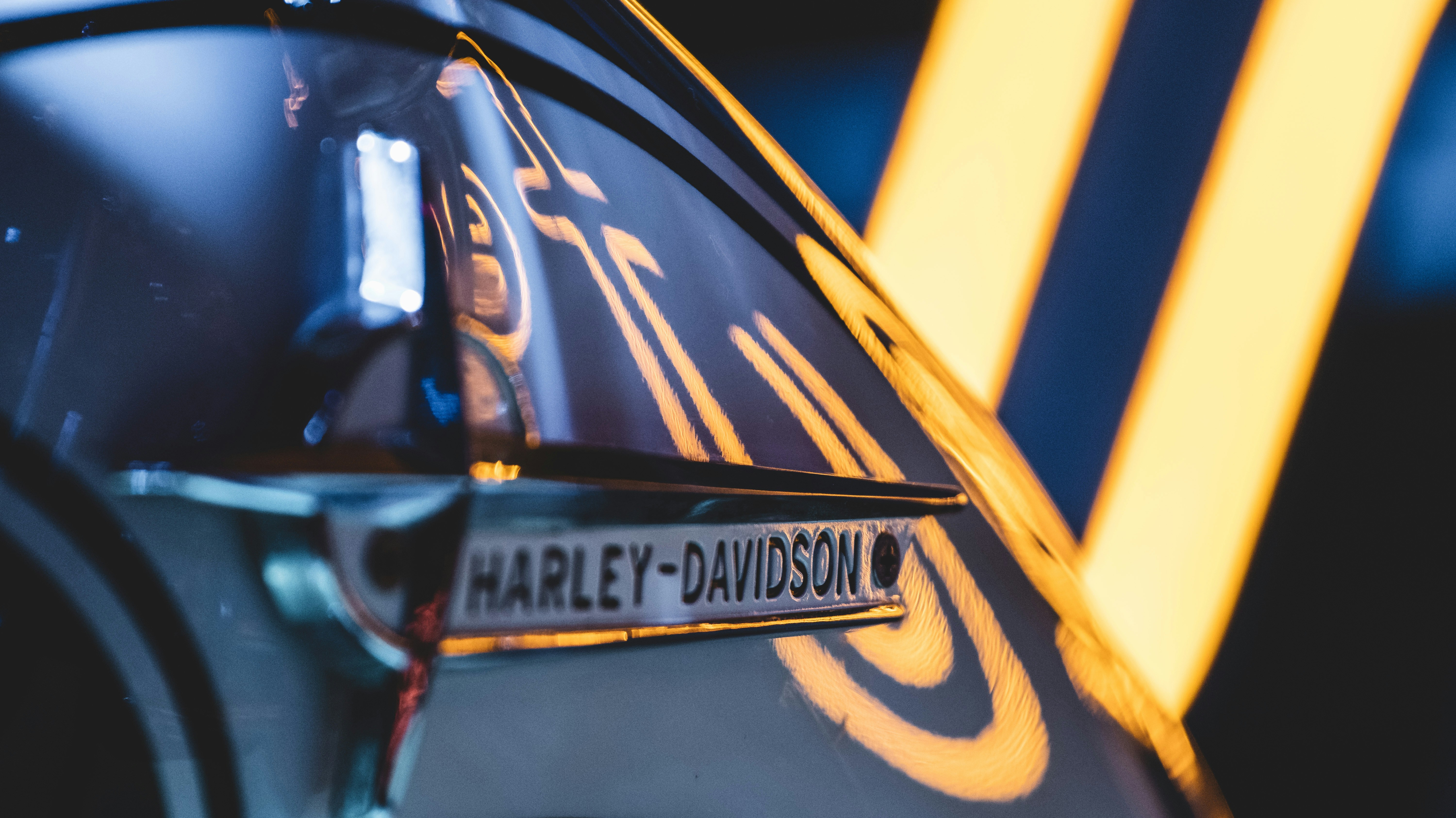Close-up of a Harley-Davidson emblem reflecting vibrant neon lights. The image captures the spirit of freedom associated with motorcycle culture.