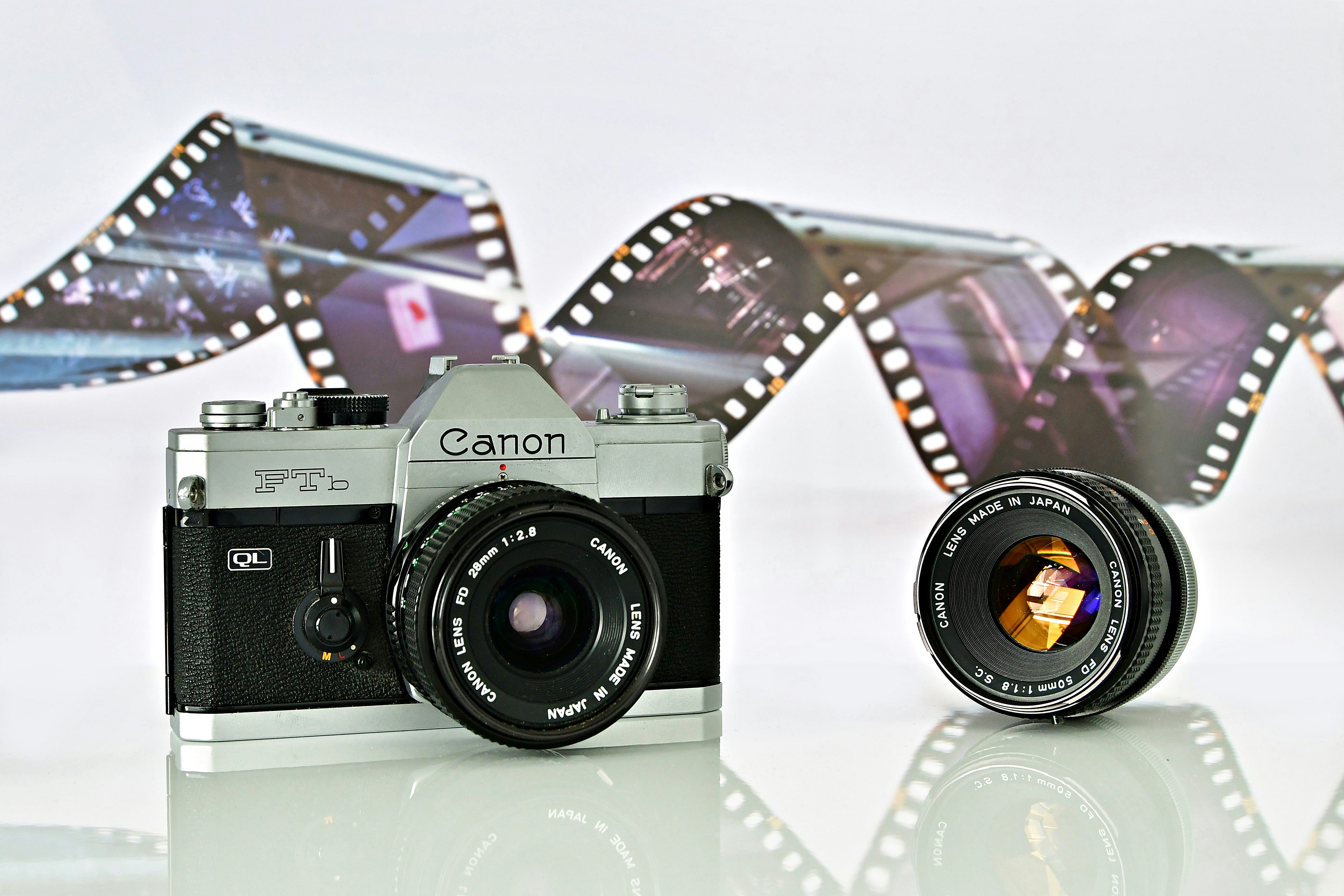 Vintage Canon SLR Paired with an Extra Lens, Framed by a Spooling Film Strip