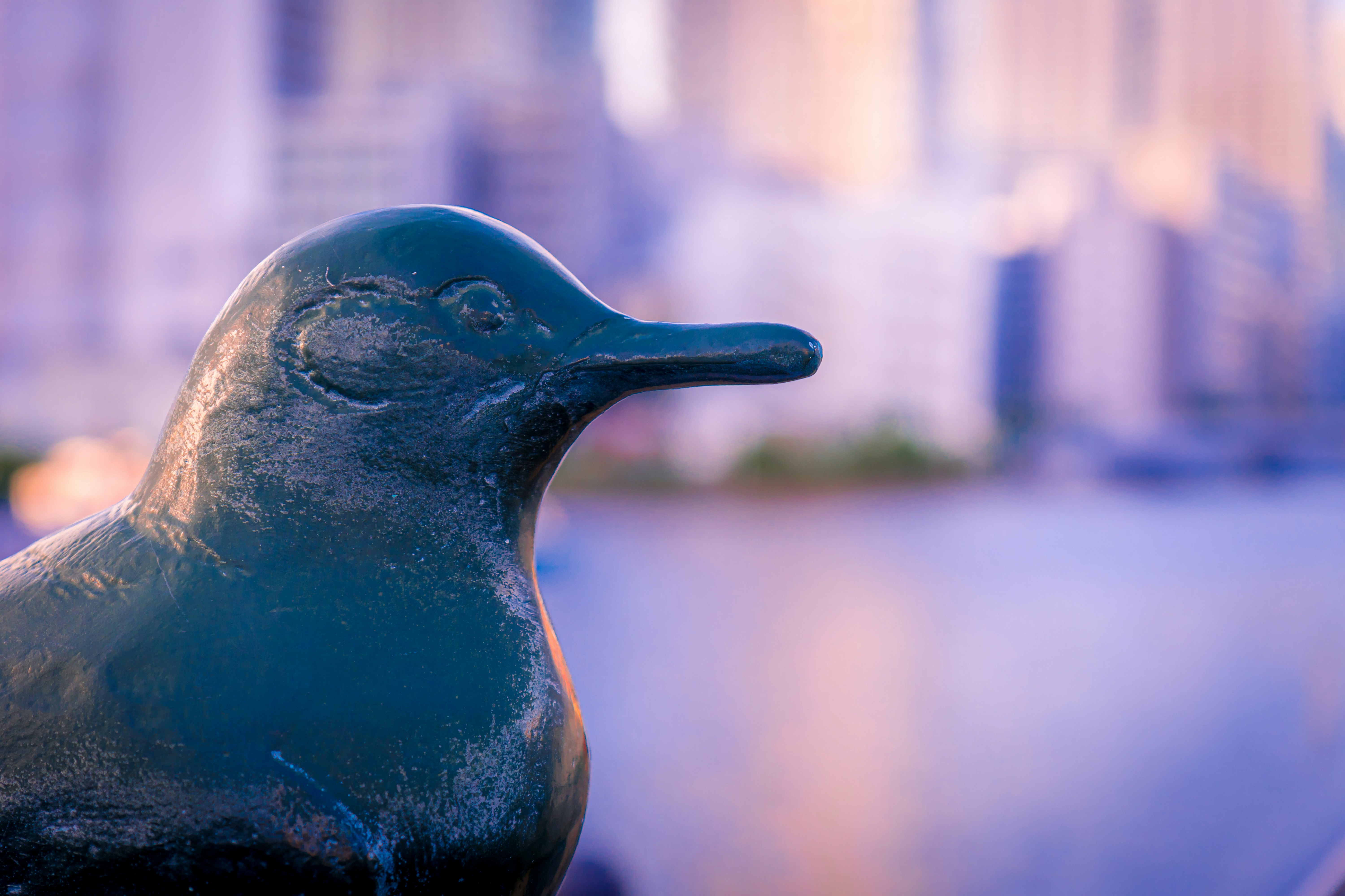 Blue Hour Sentinel: Close-up of a Bronze Bird Against a Misty City Backdrop