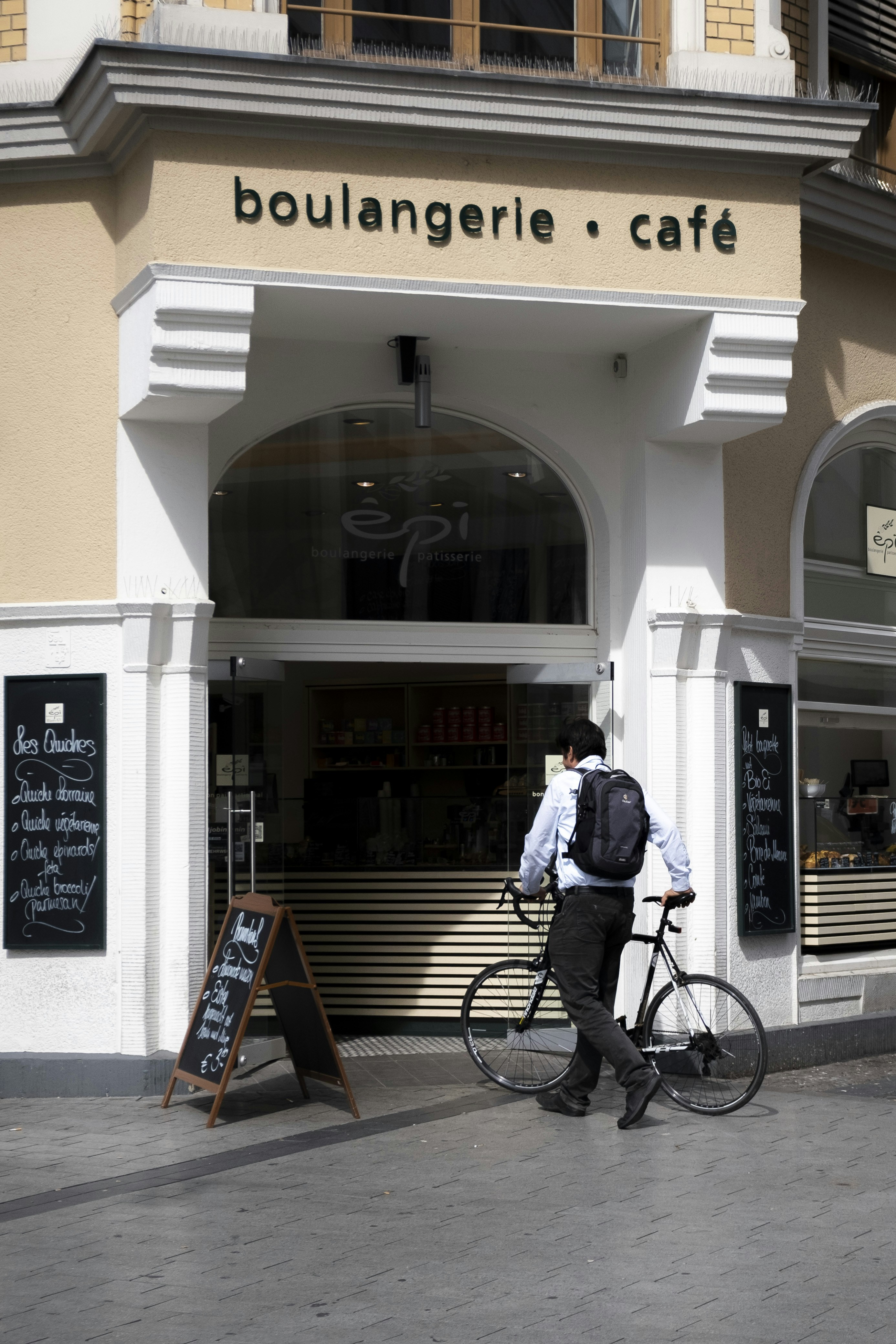 Cyclist at the Threshold of a Sunlit Paris Boulangerie